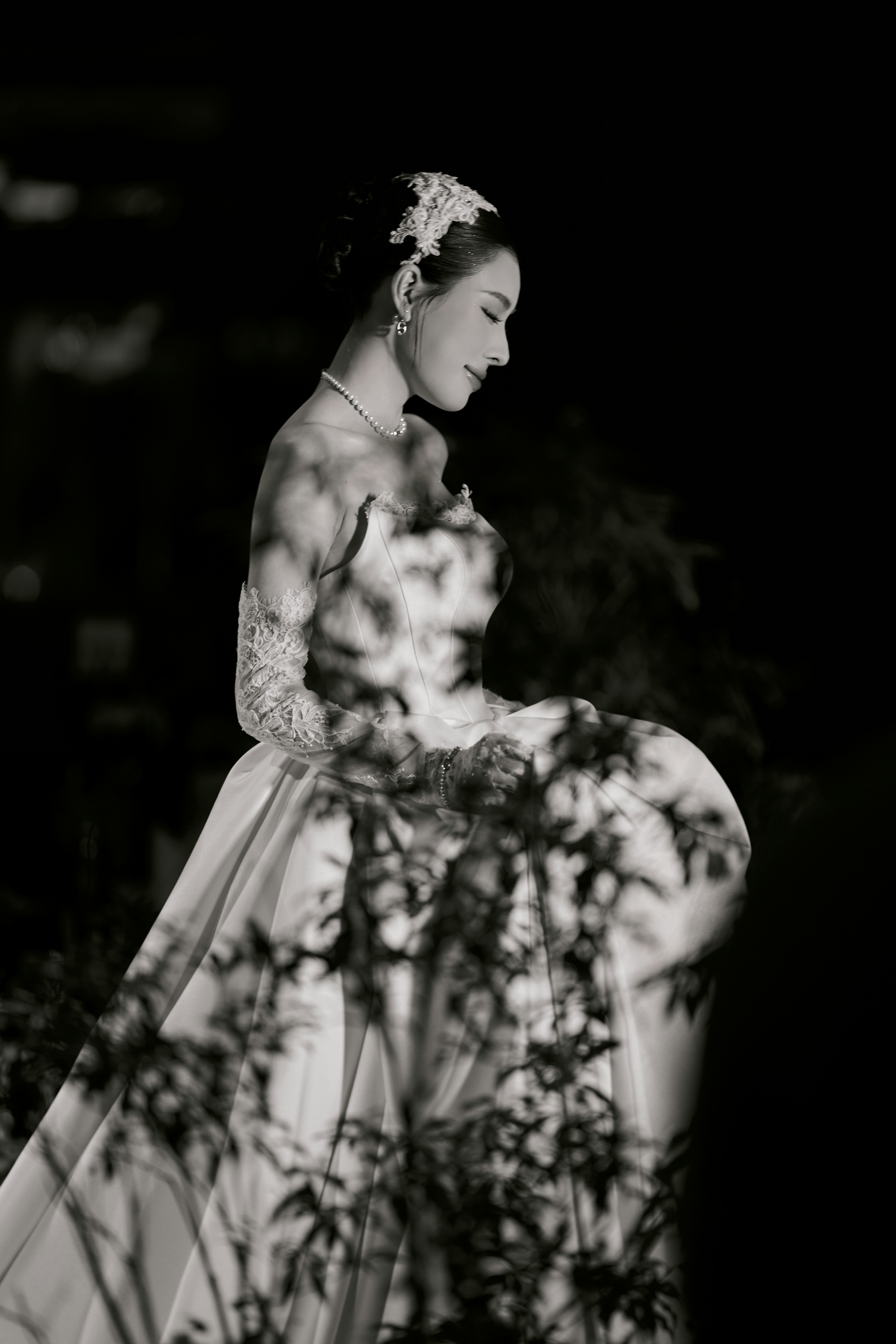 Bride in Shadowed Grace: A Quiet Portrait Through Veiled Foliage