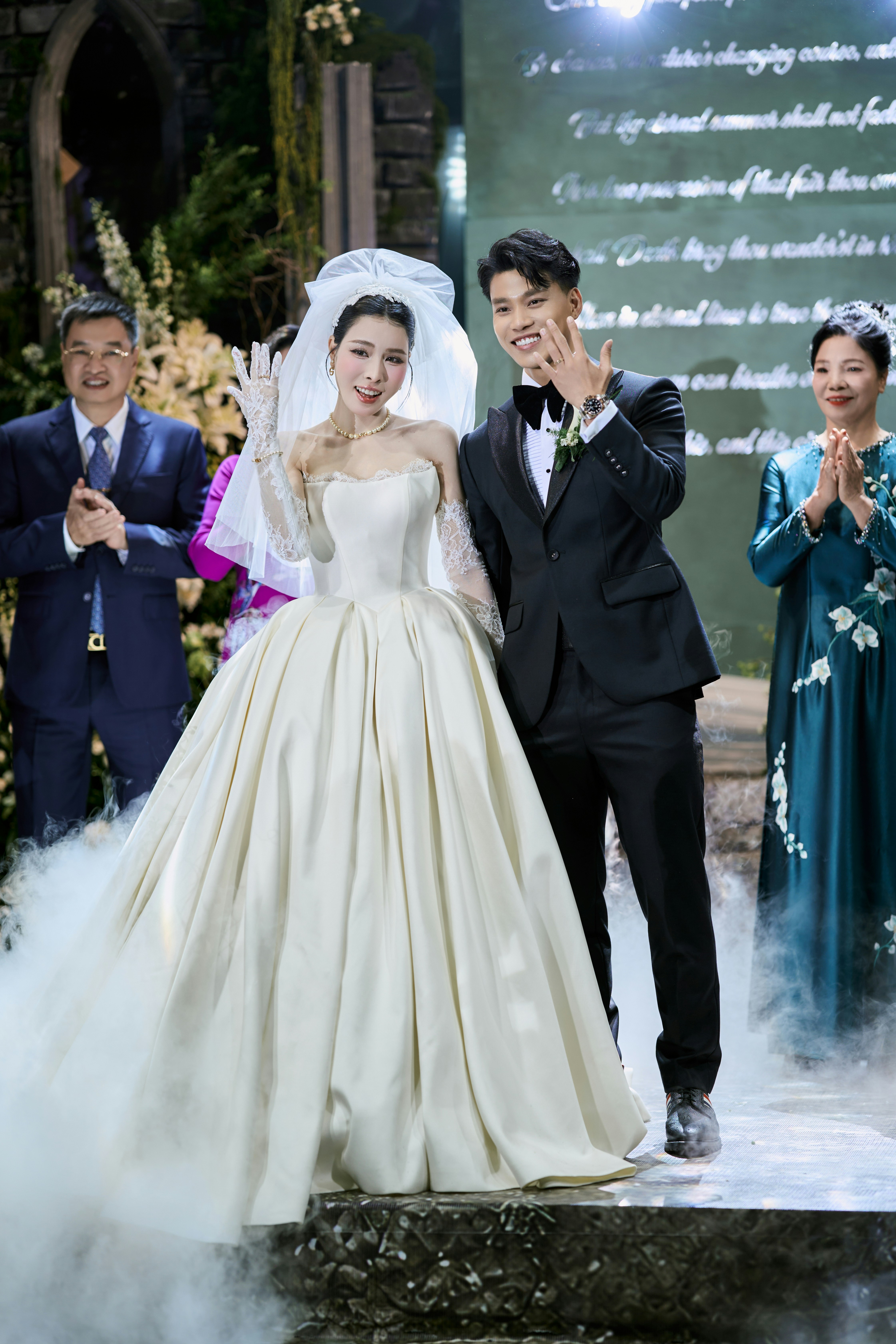 Bride and groom on stage: a luminous wedding moment beneath floating fog