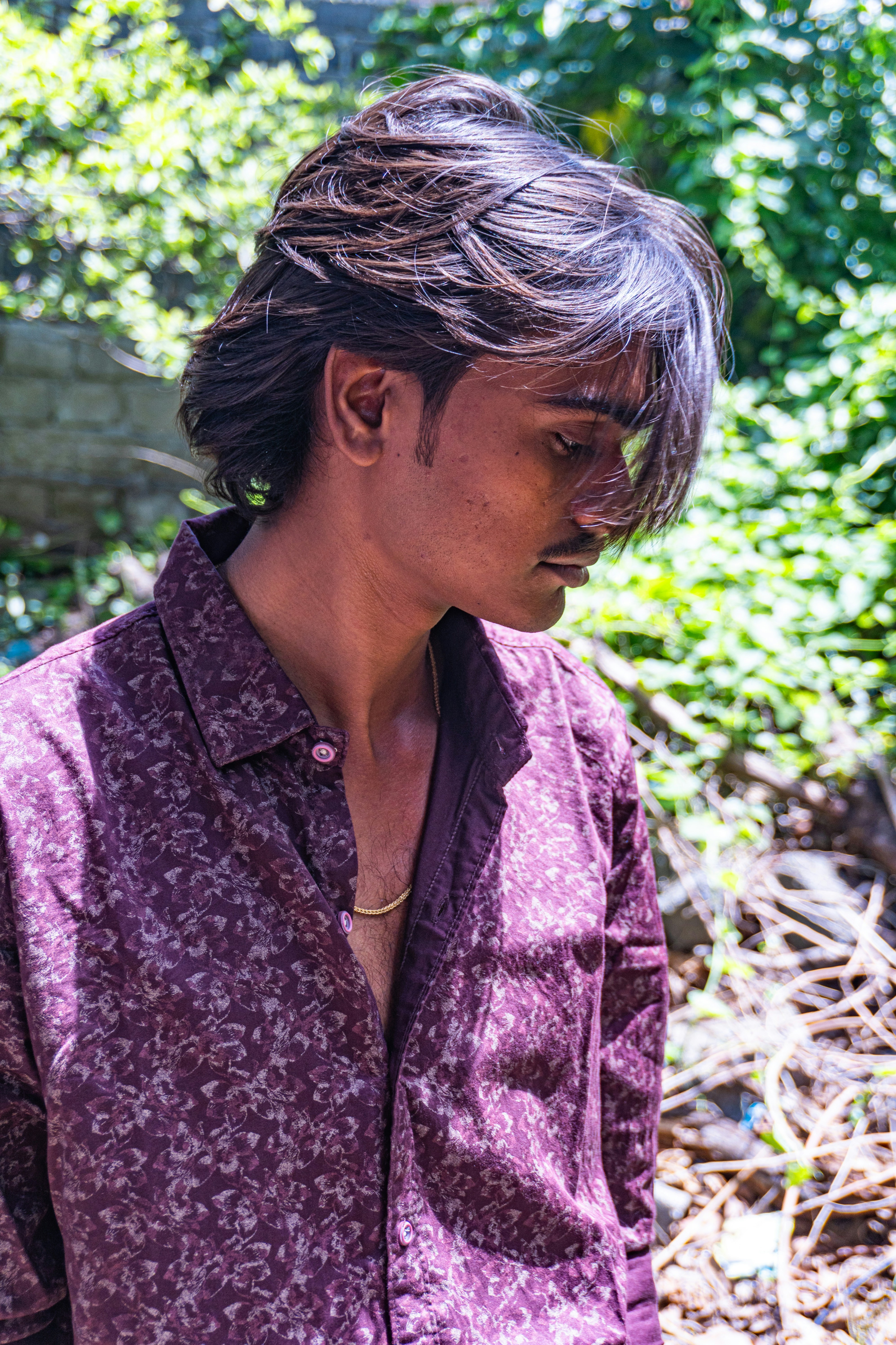 Profile in Sunlit Garden: A contemplative moment in a patterned burgundy shirt