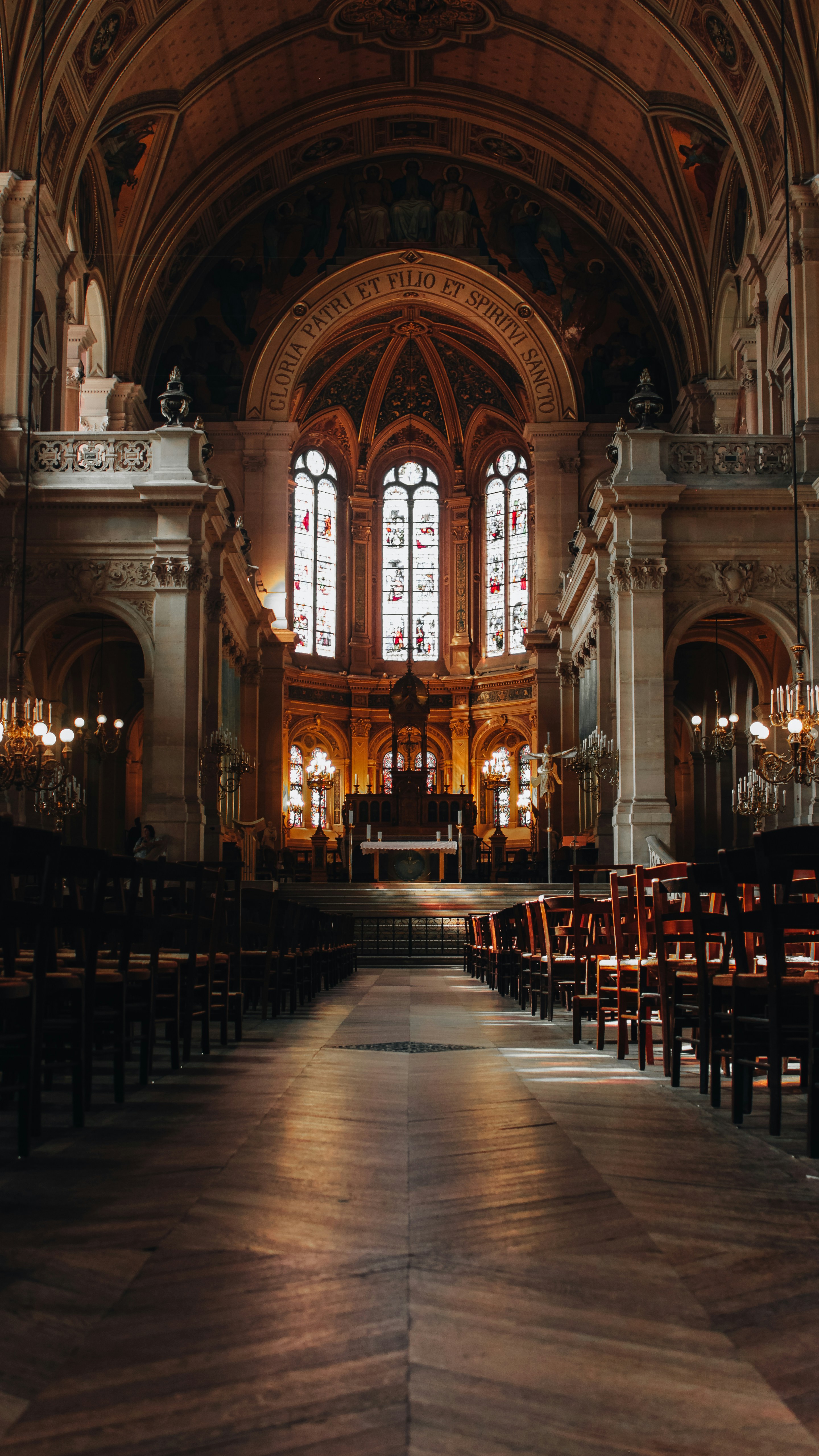 Cathedral Aisle Toward the Altar: Lantern-lit Vaults and Stained Glass