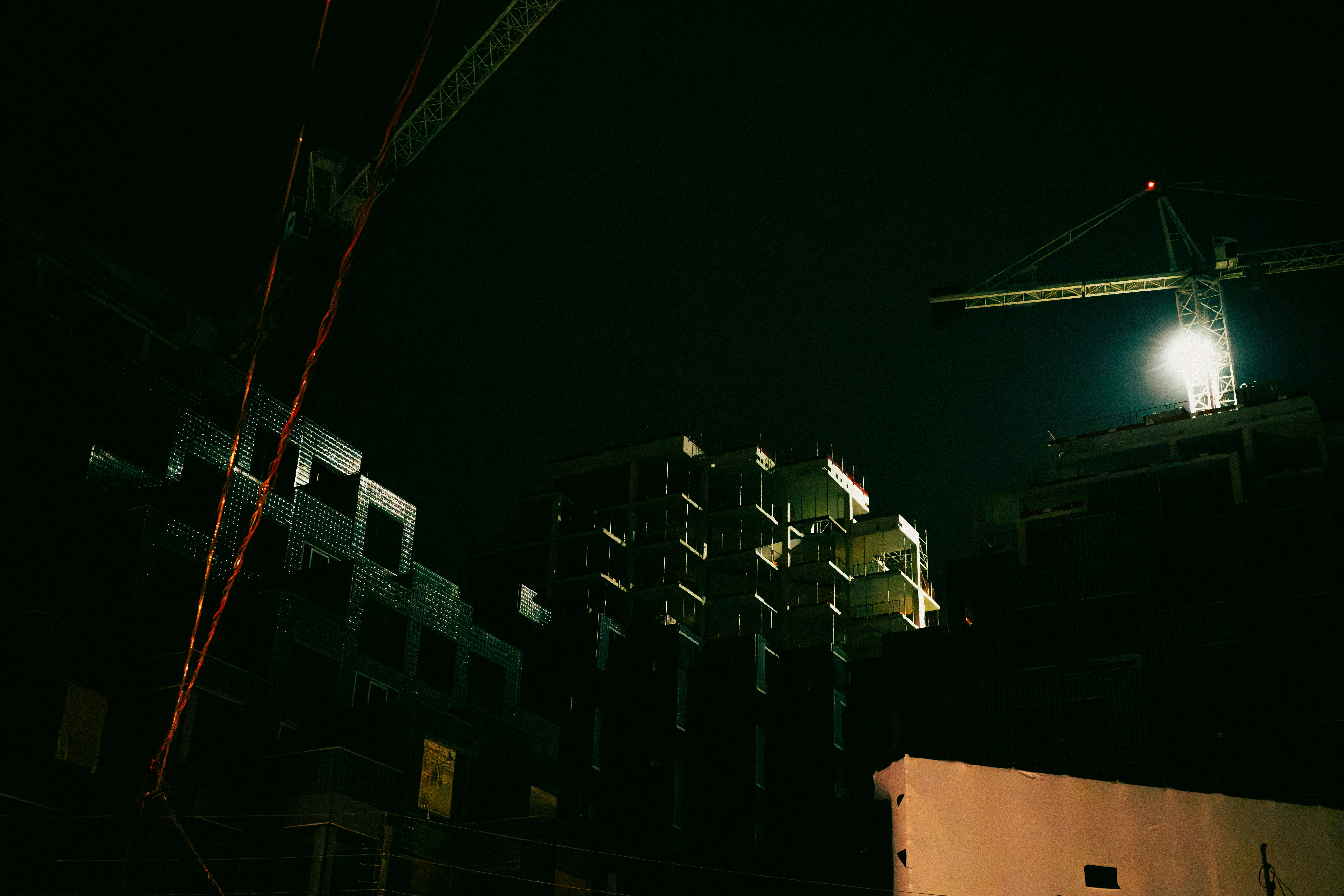 Crane Beams and Stacked Silhouettes Beneath Night Construction