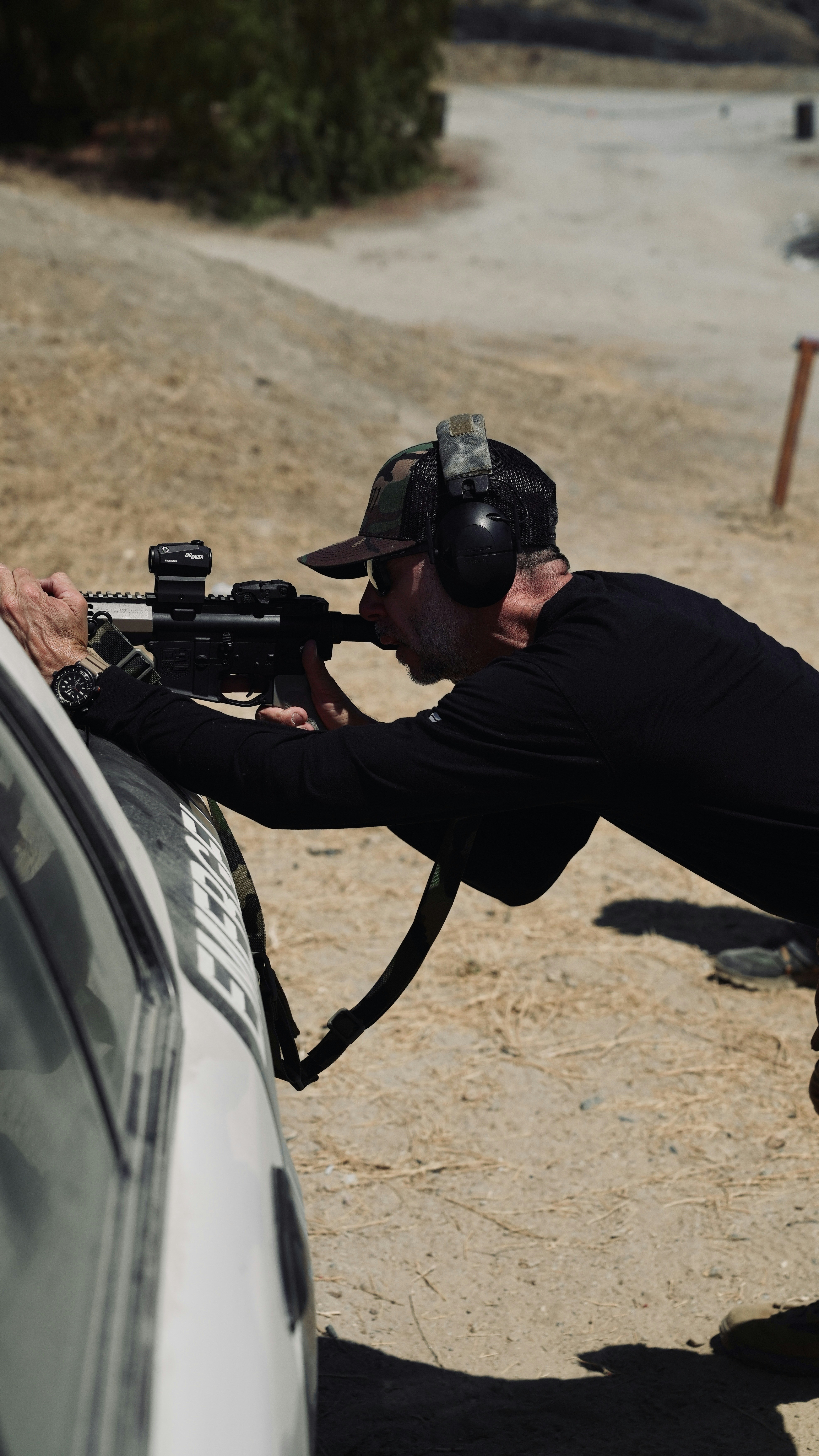 Firearms instructor (Jarret Waldman) aiming down the sights of a rifle during a firearms safety course at a private range.