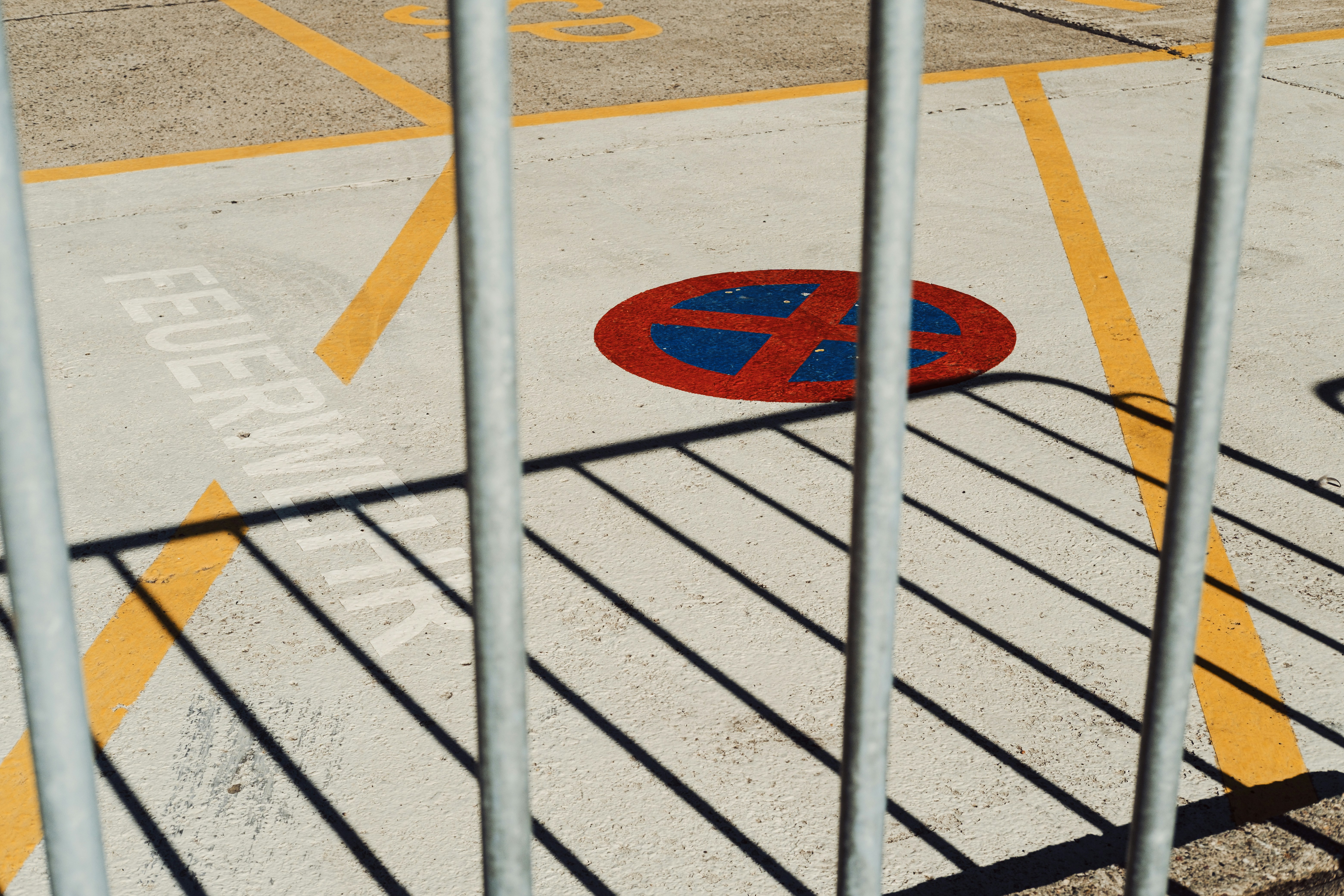 Lines and Shadow: Urban Fence Casting Stripes on Concrete