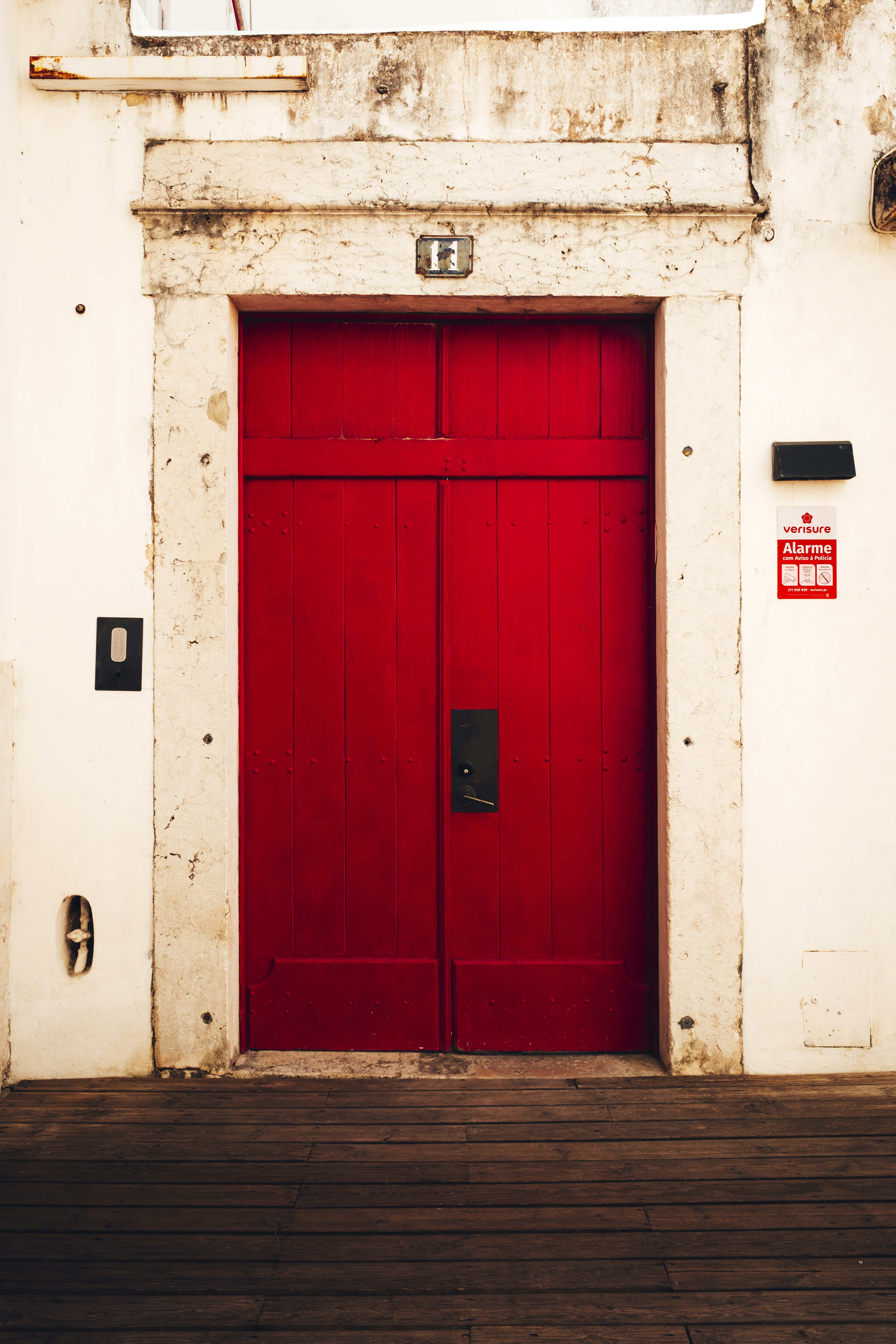 Crimson Portal: A Buttery-Red Door Framed by Weathered White Wall
