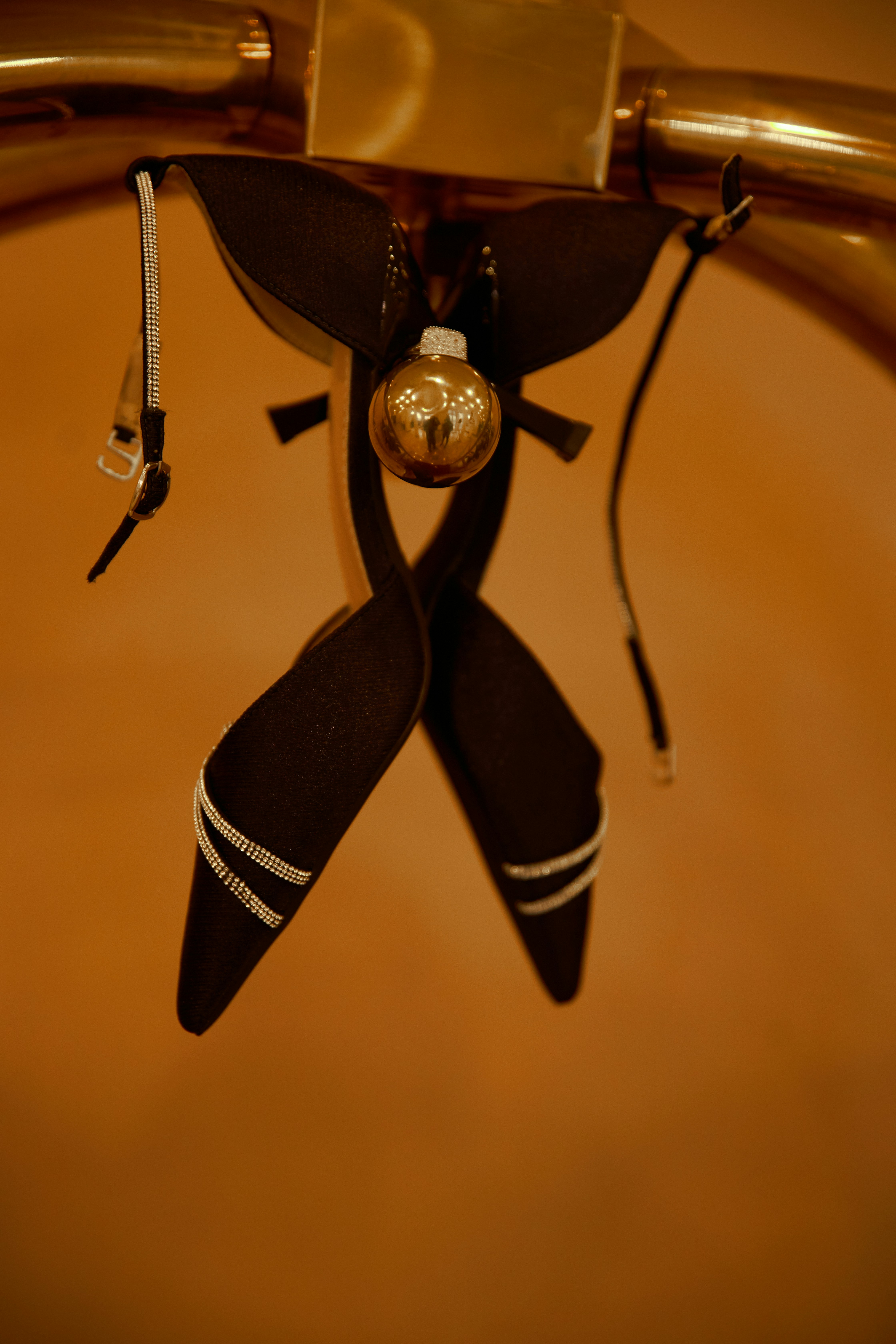 Suspended Ornament: A Close-Up of a Metallic Ball and Ribboned Ties Under Warm Glow