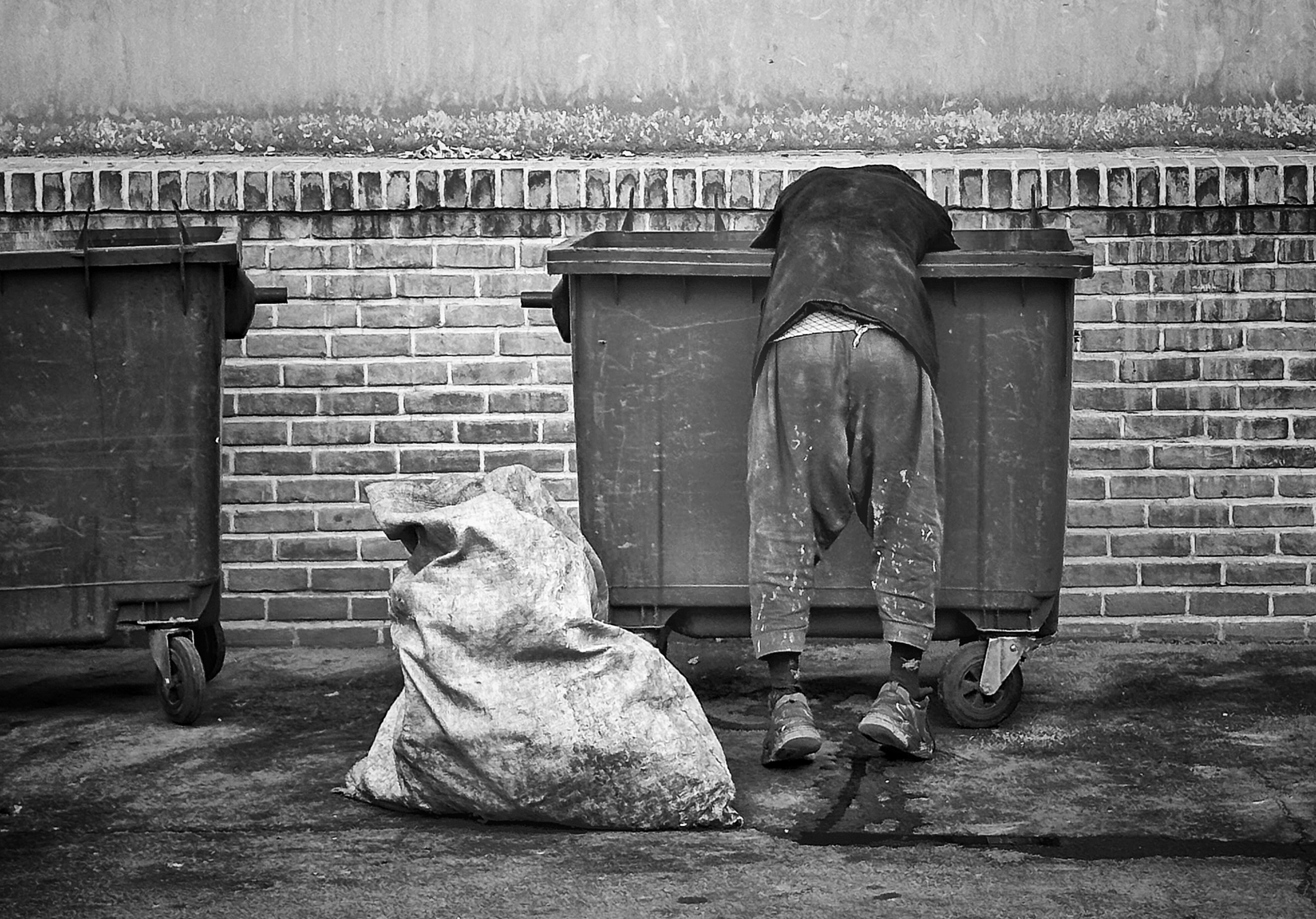 In the Shadow of the Dump: A Figure Bends Over a Tidy Chaos