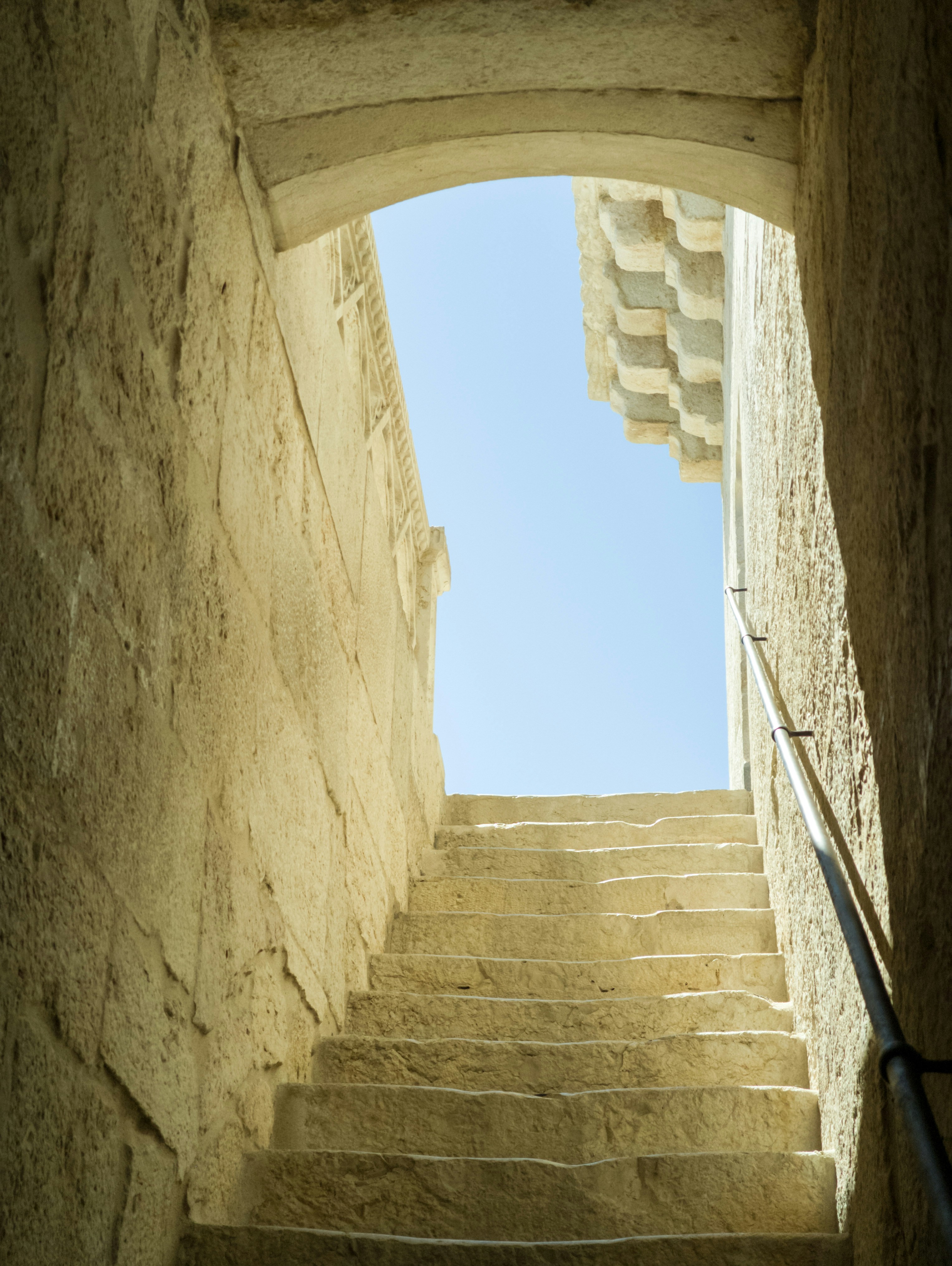 Ascending Light: Sunlit Stone Staircase to a Skyward Arch