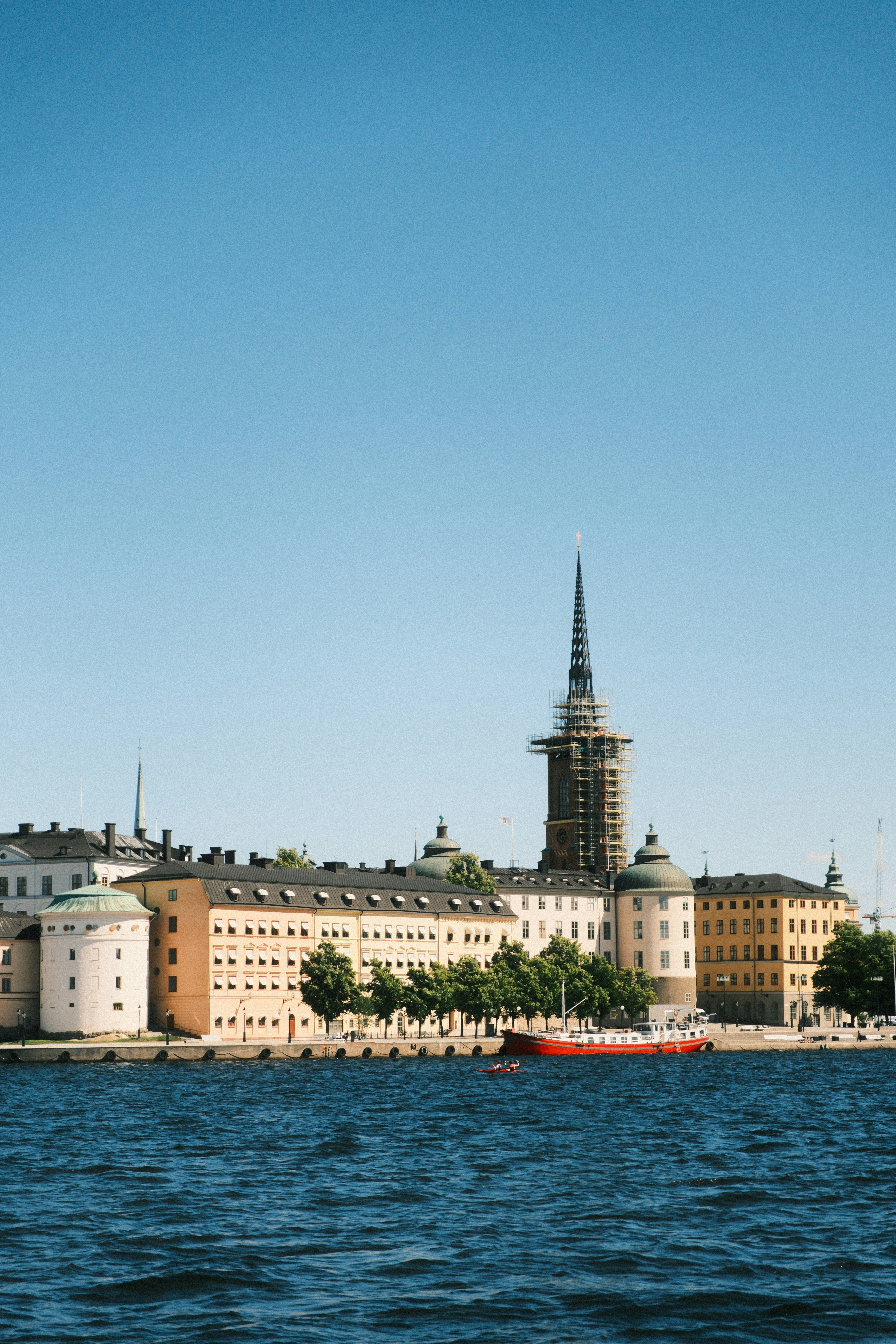 Harbor skyline anchored by a church spire under a clear afternoon sky