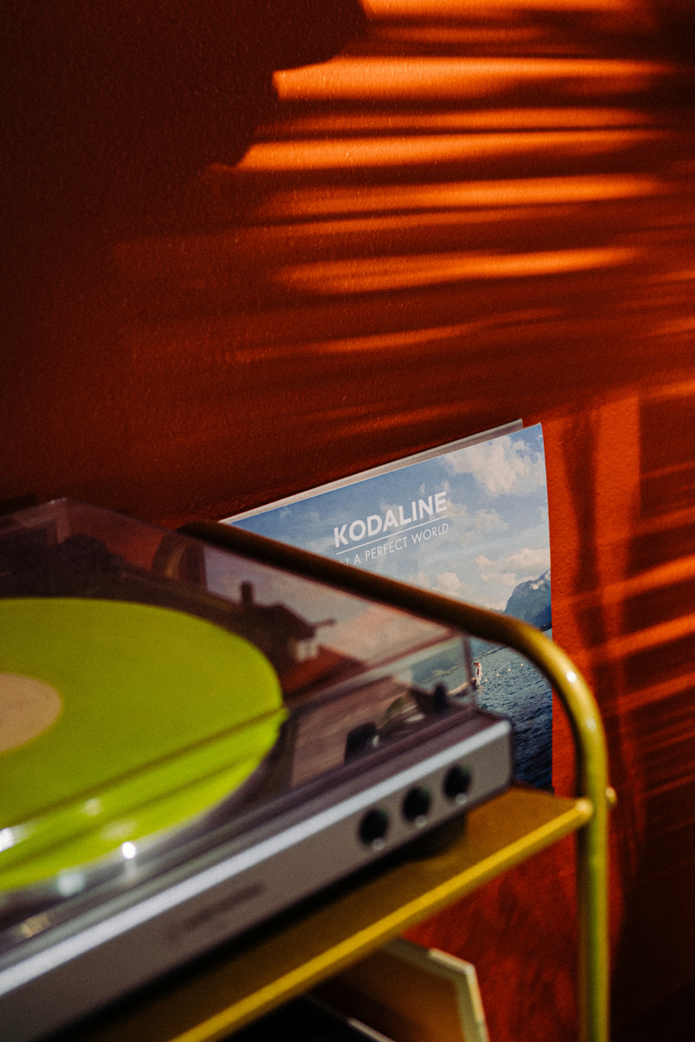 Vinyl Refrain: A Record Player and a Poster Peek from a Velvet Orange Wall