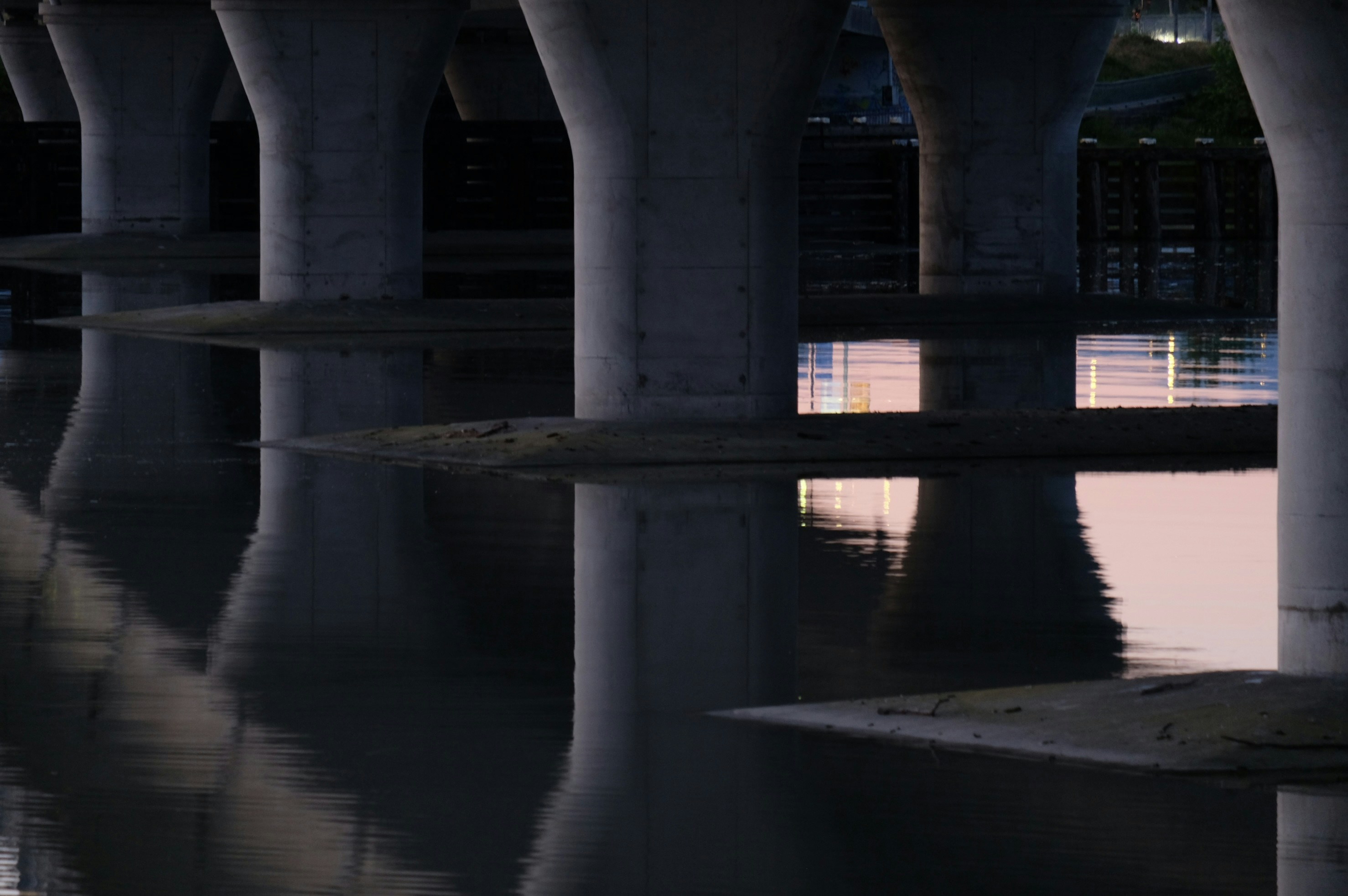 Reflections Beneath the Bridge Columns at Dusk