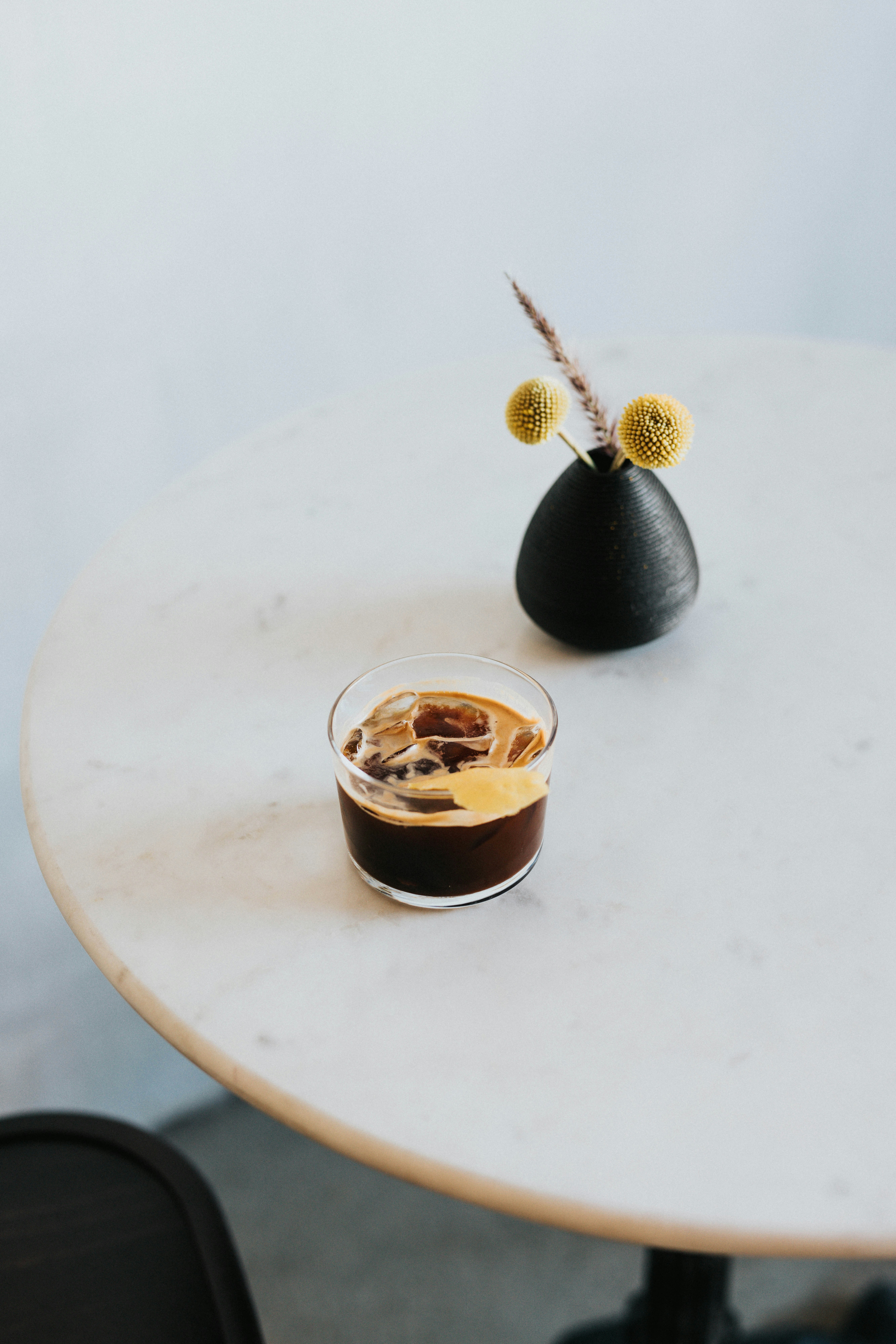 Minimalist Café Portrait: iced coffee and a black vase with yellow blooms
