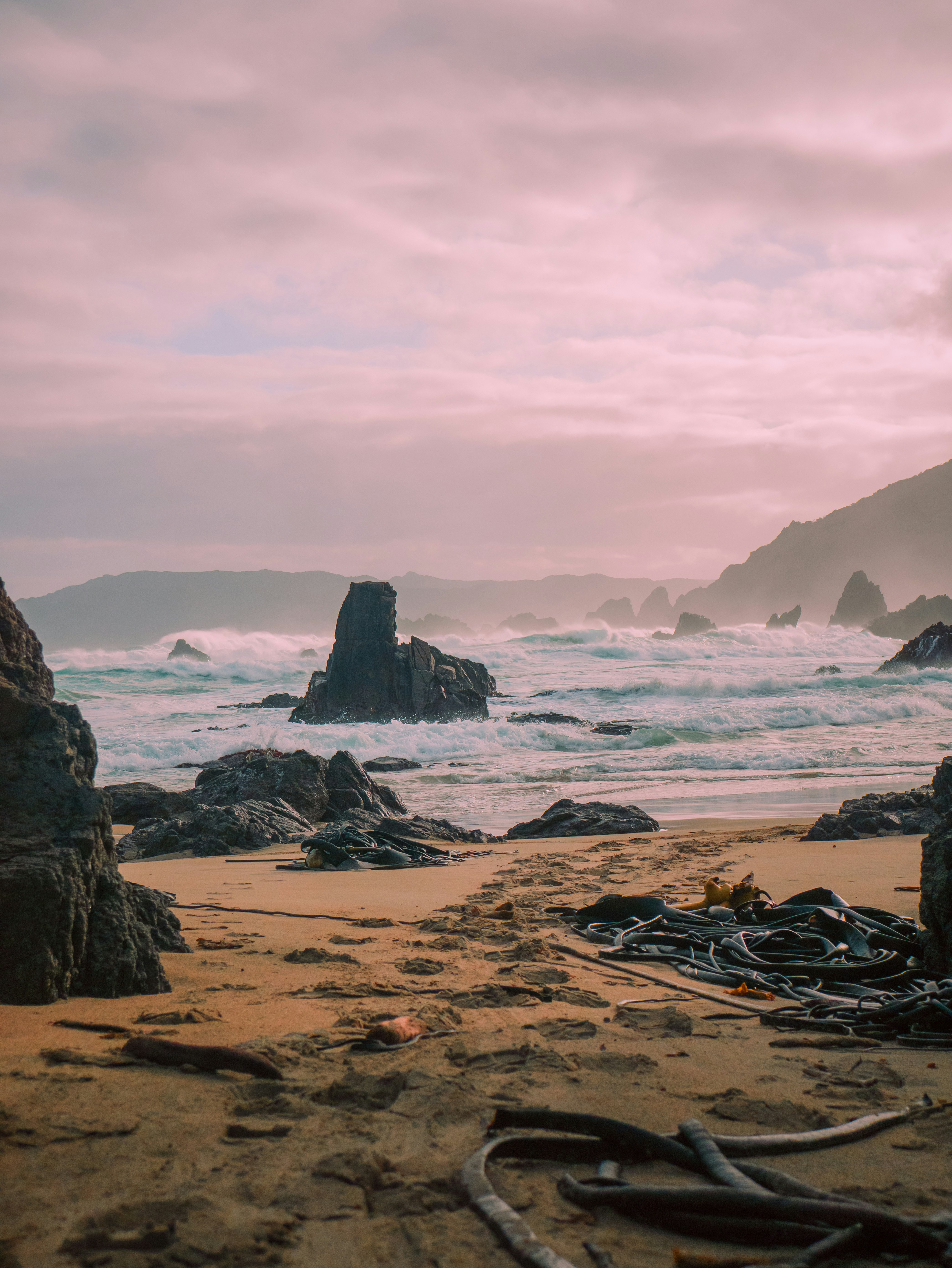 Rose-Colored Tide: A Rugged Beachscape with Jagged Rocks