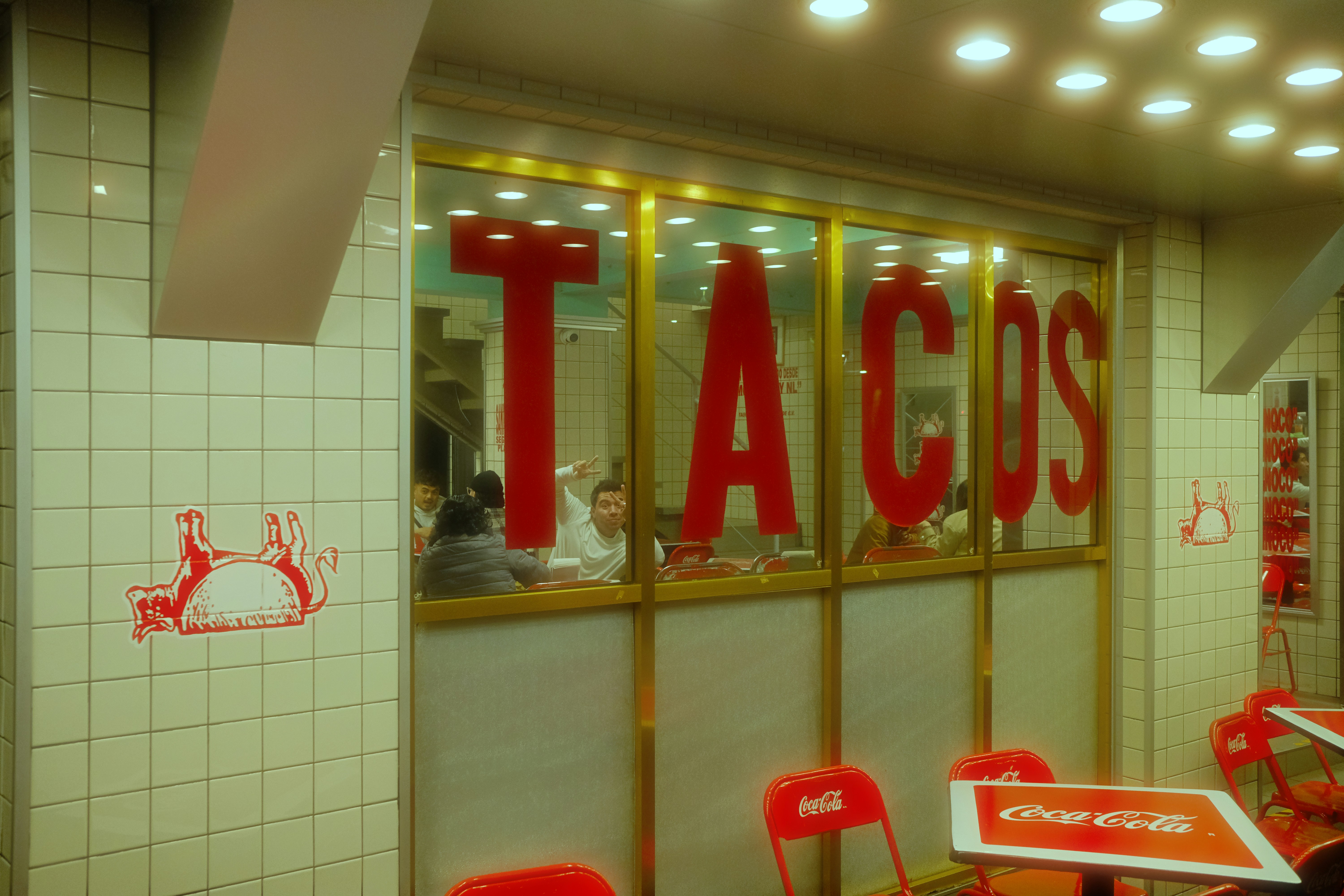 Neon Taco Window: Red Chairs and Taco Sign Reflected in a Retro Diner