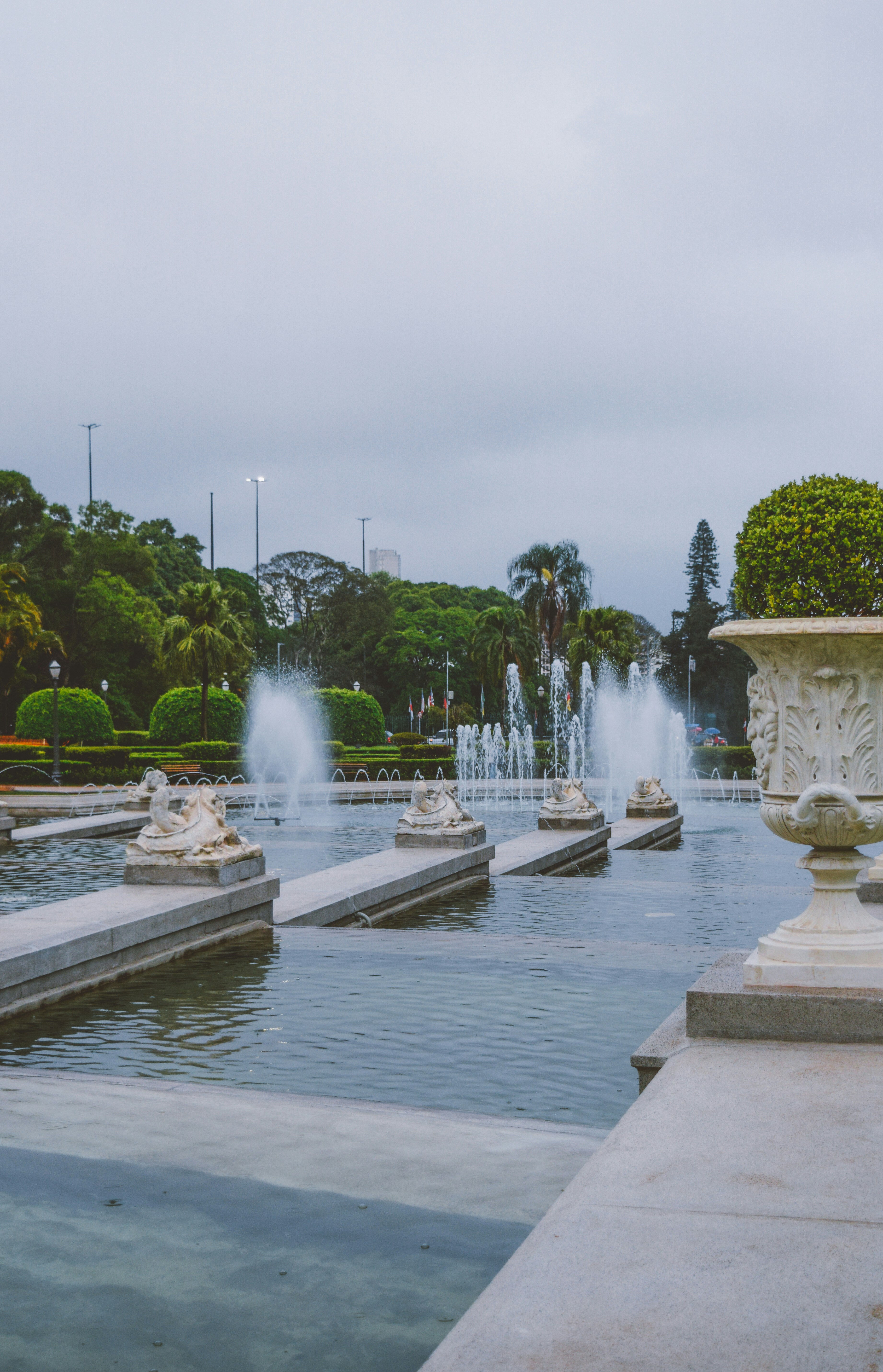 Symmetrical Fountain Vista: Carved Vases and Cascades in a Calm Park Pool