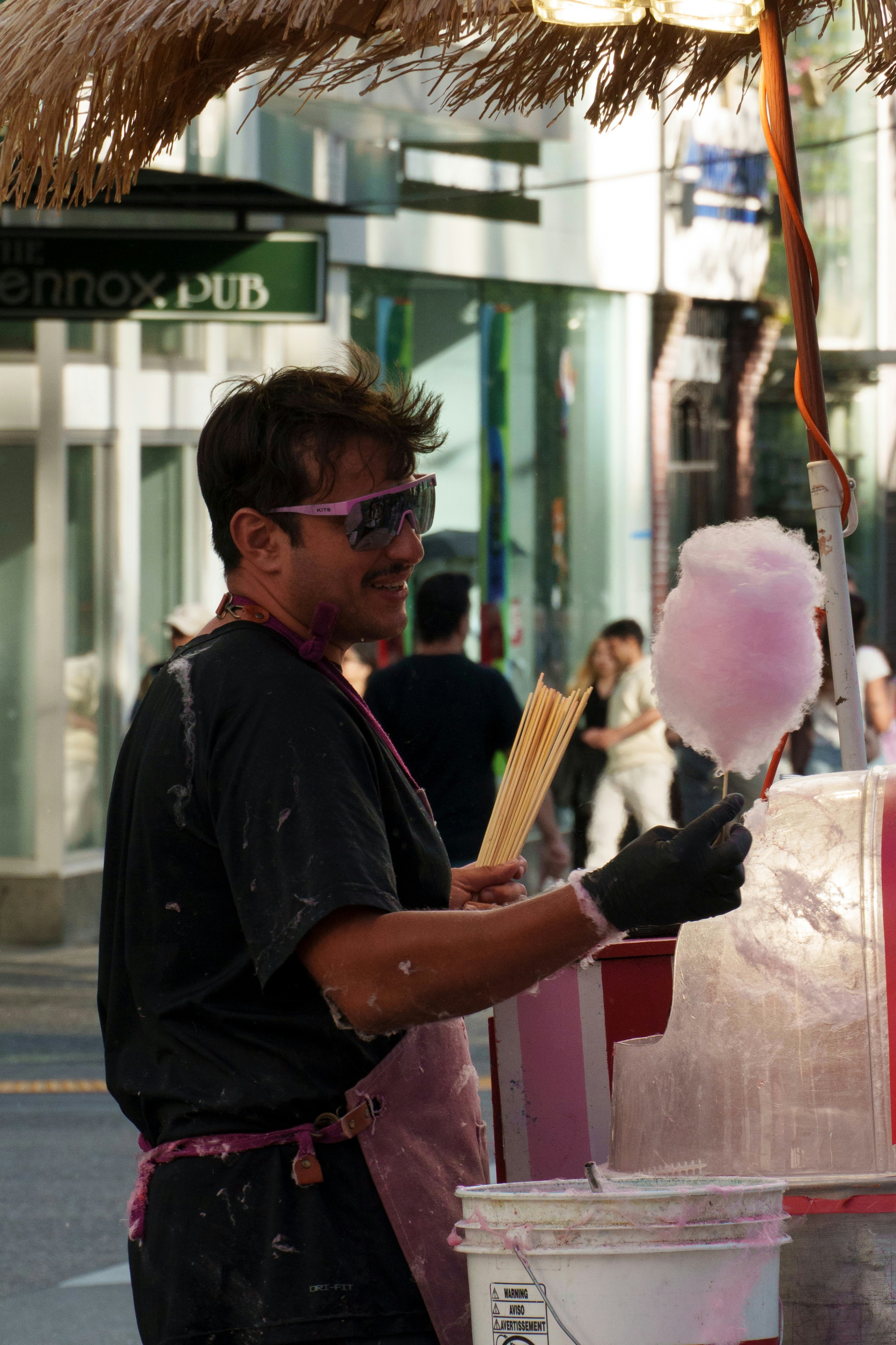 Cotton Candy Vendor in the Street Light, a Moment Beneath a Straw Canopy