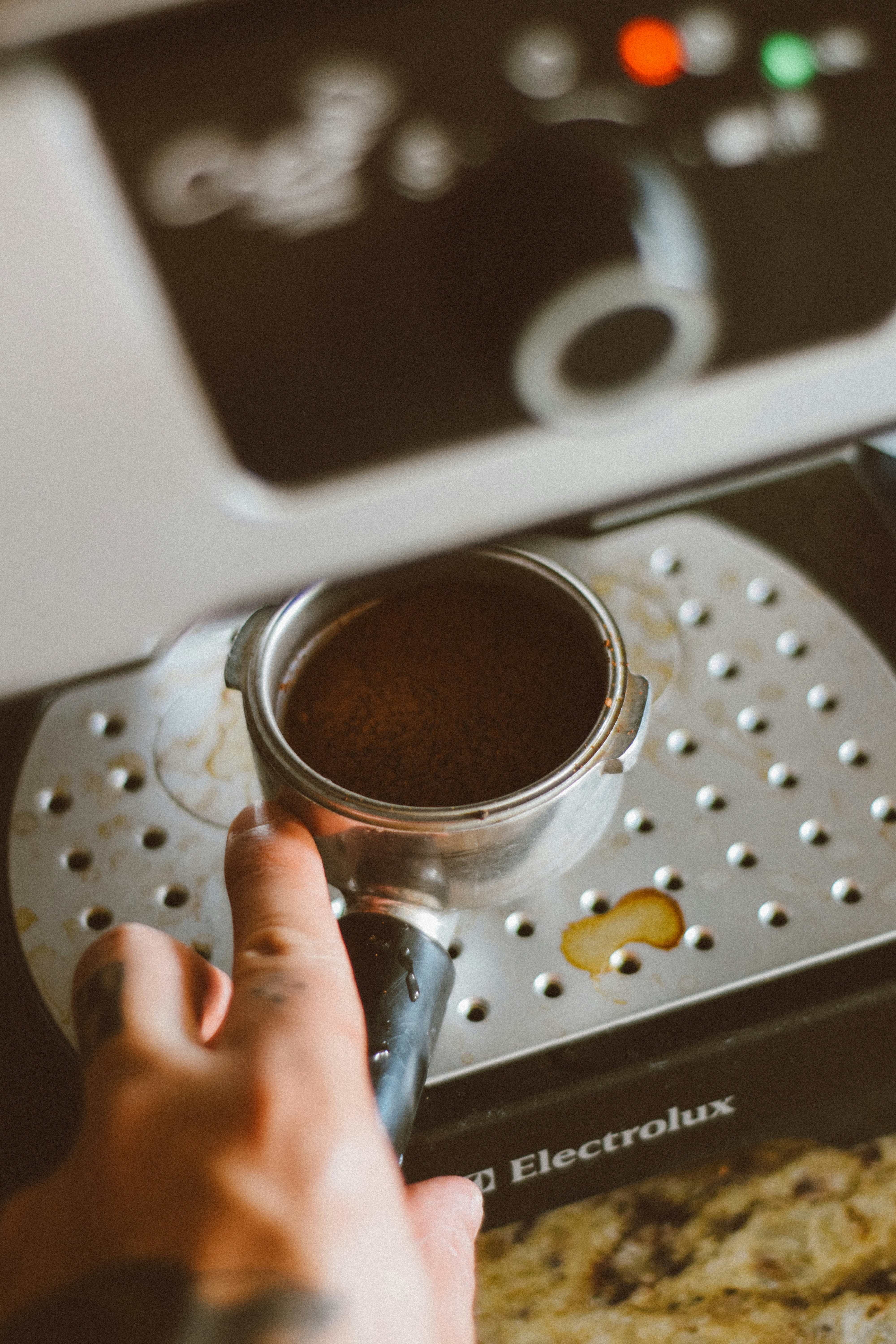 Steam rises from the espresso portafilter as a hand steadies the machine