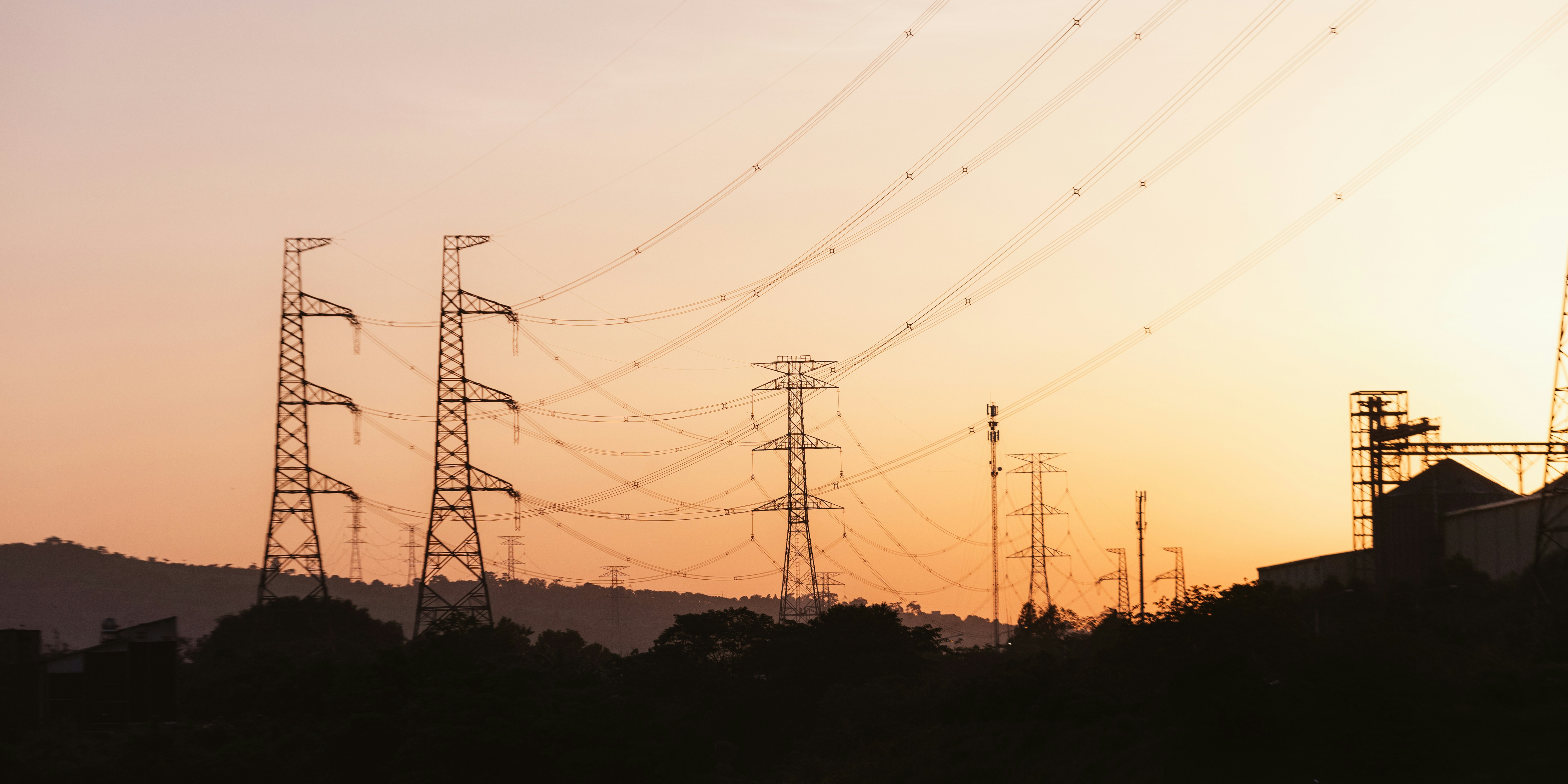 Sunset Over the Grid: Power Lines Silhouetted Against a Quiet Horizon