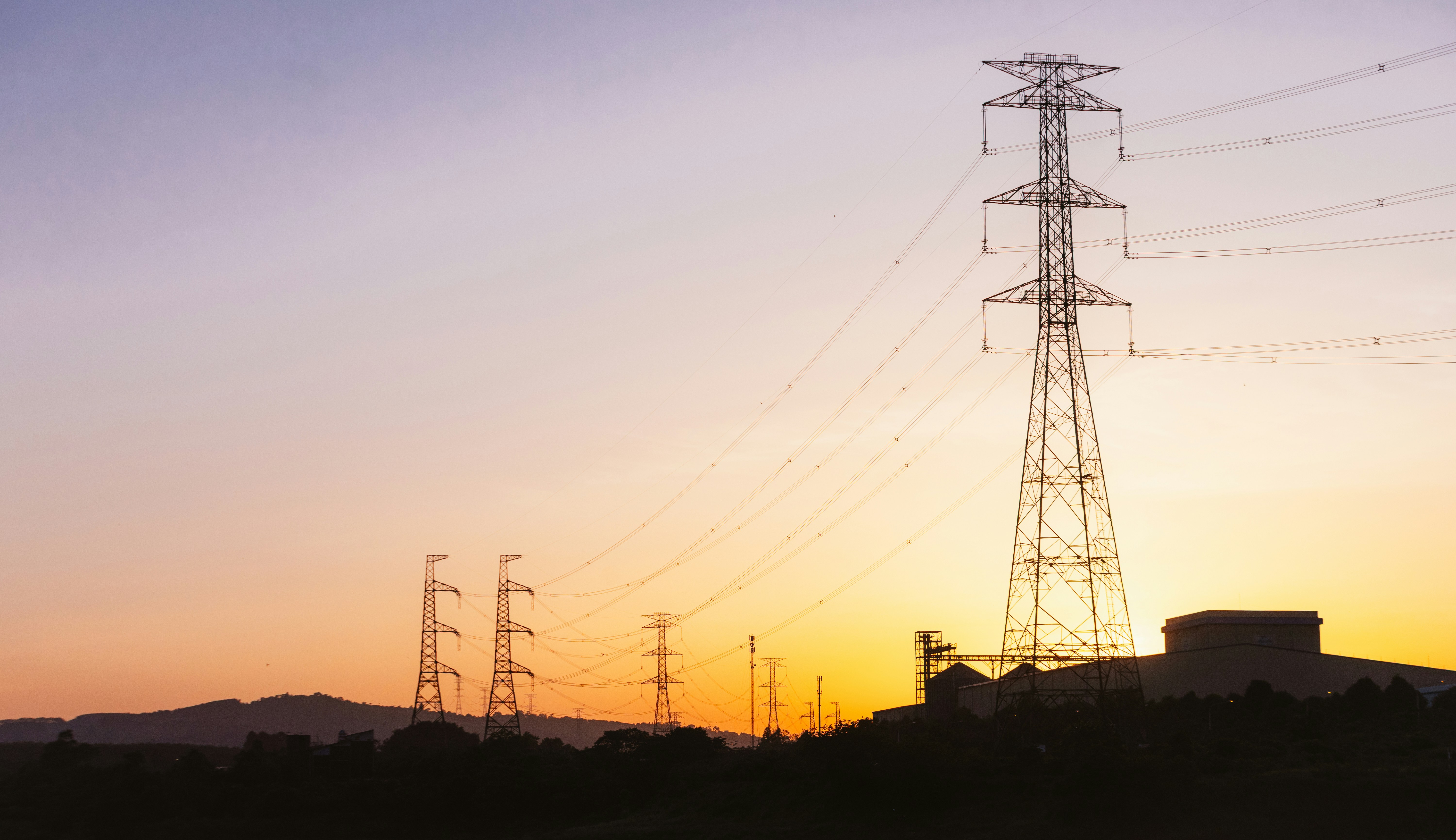 Sunset Gridlines: silhouette of transmission towers against a fading horizon