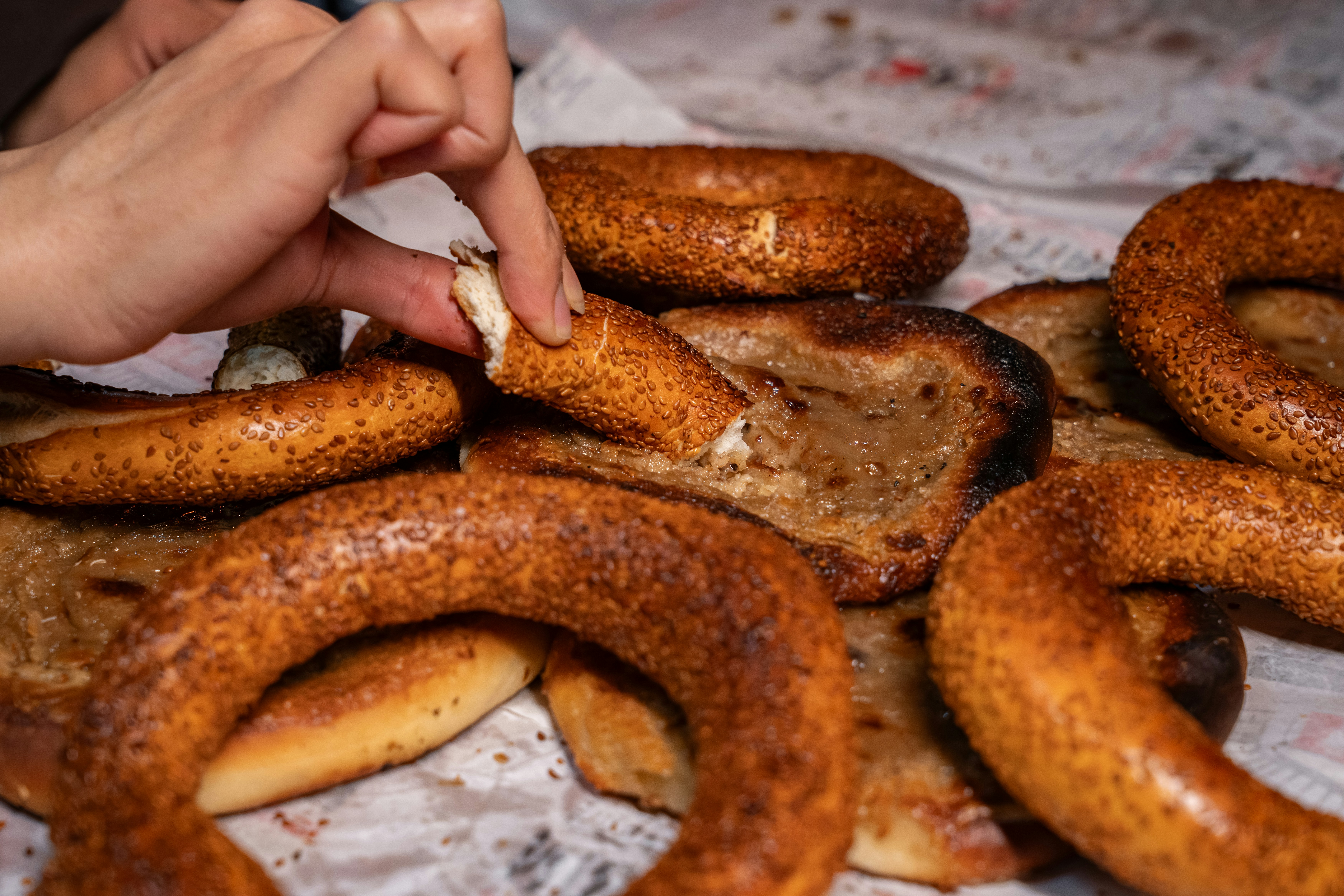 Hands Grab Freshly Toasted Bagels from a Sticky Tray