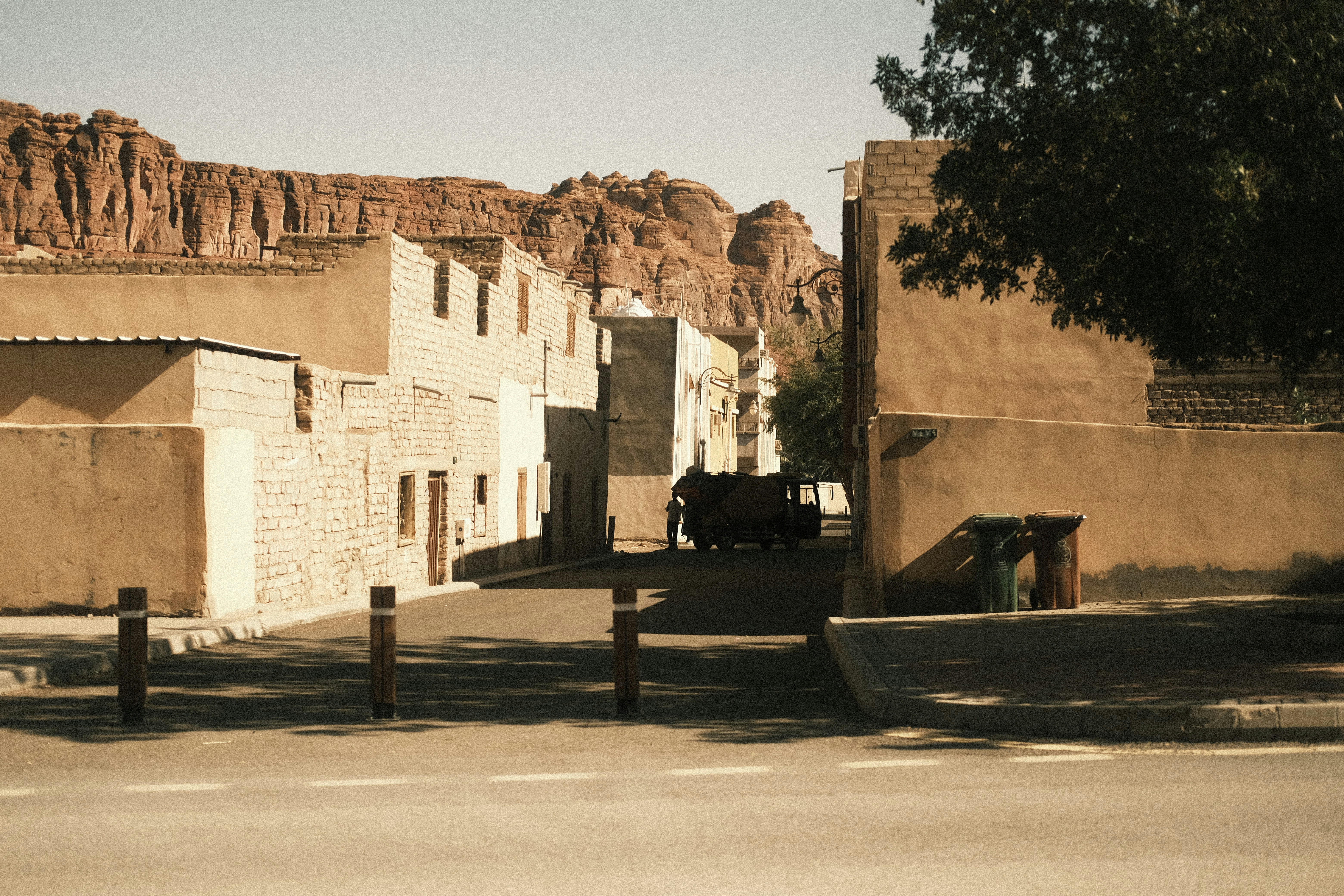 Deserted Street Between Adobe Walls and Shadowed Vehicle
