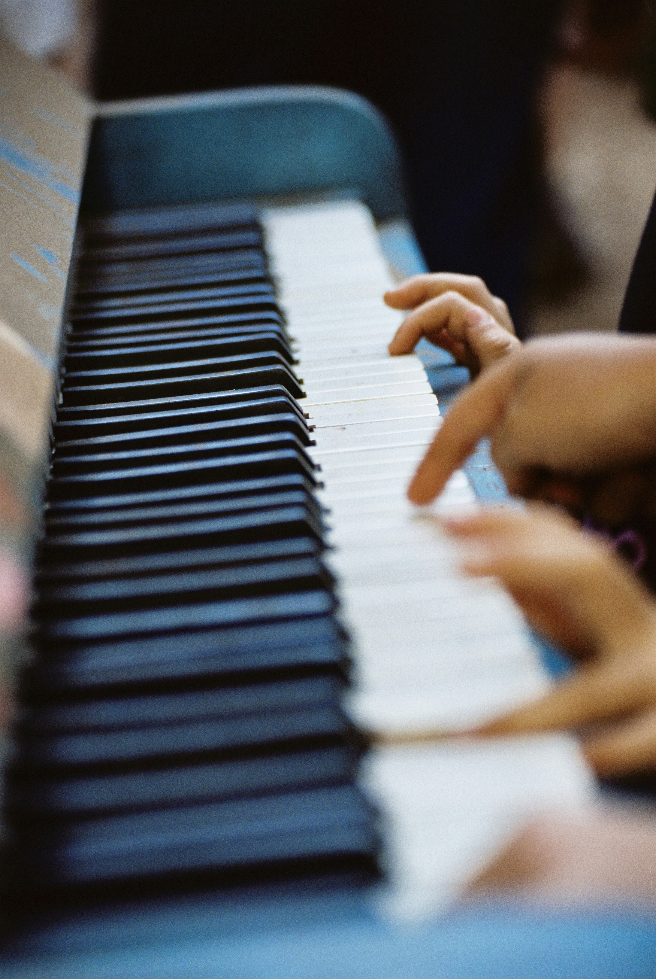 Close-up of a pianist's hands gliding over piano keys, capturing motion and rhythm in a candid moment. The focus emphasizes finger work and the instrument's keyboard.