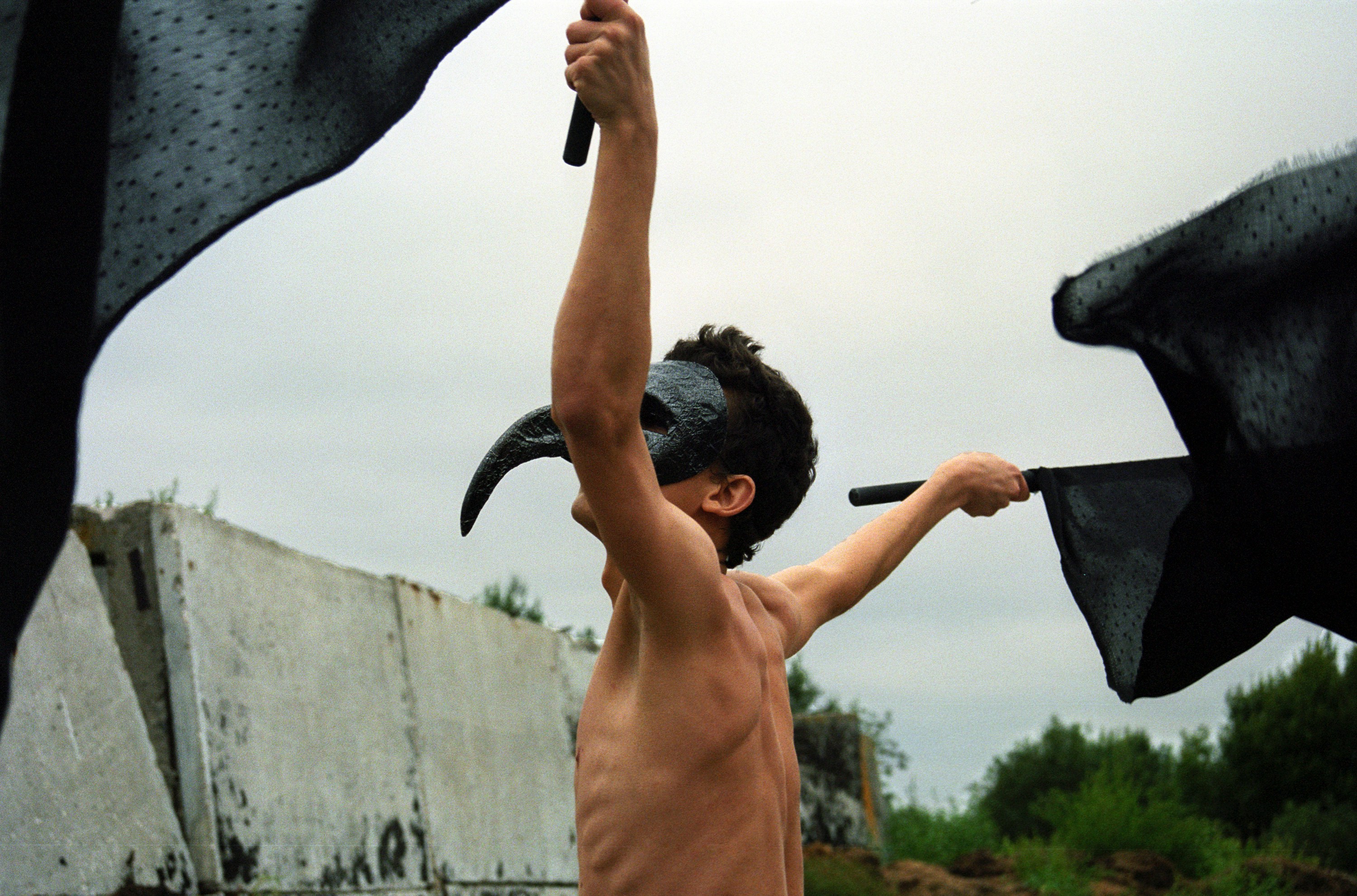 Masked Warrior Amid Tattered Flags: A Moment of Defiant Lift