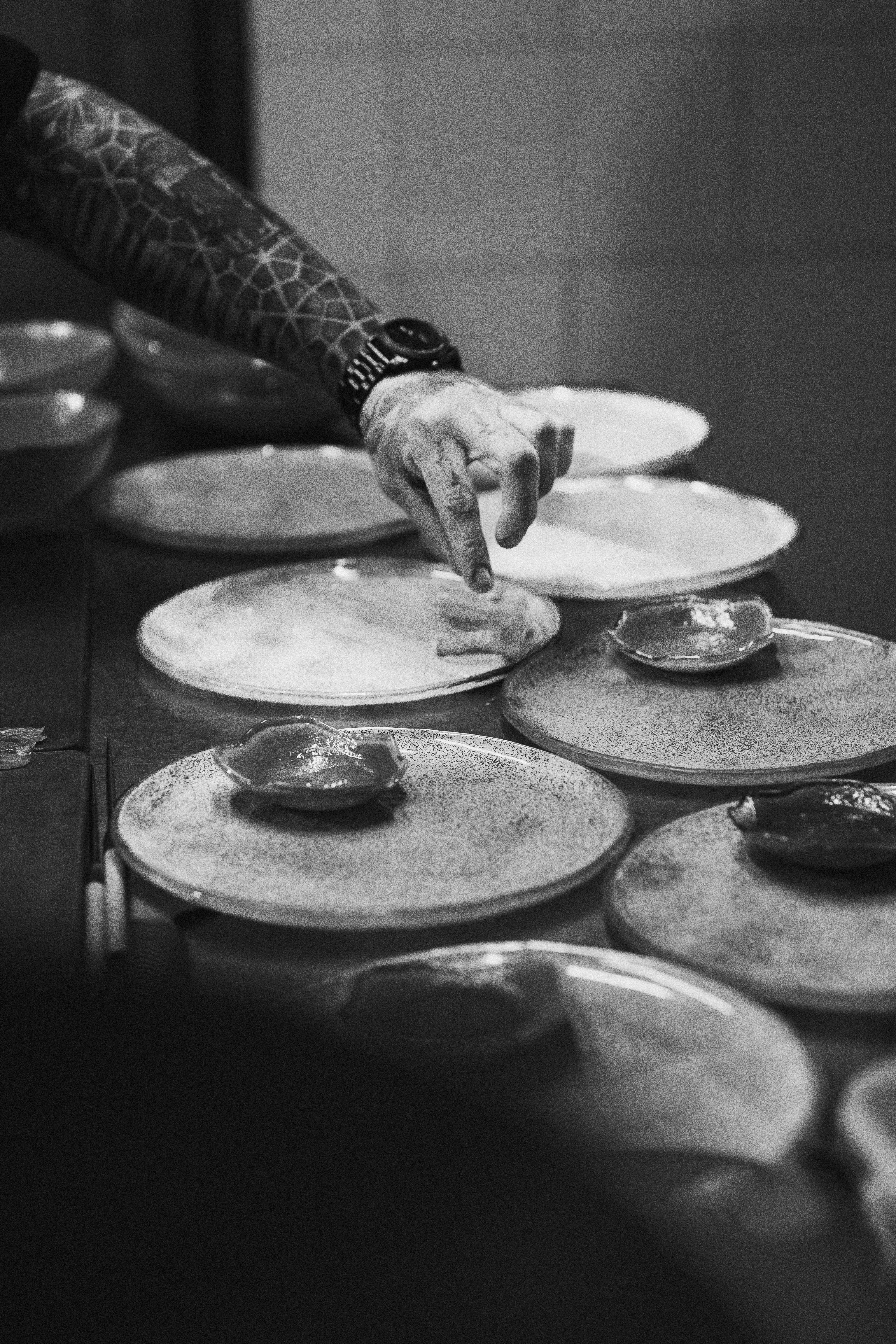 Hands Over Ceramic Plates: A Quiet Kitchen Moment in Monochrome