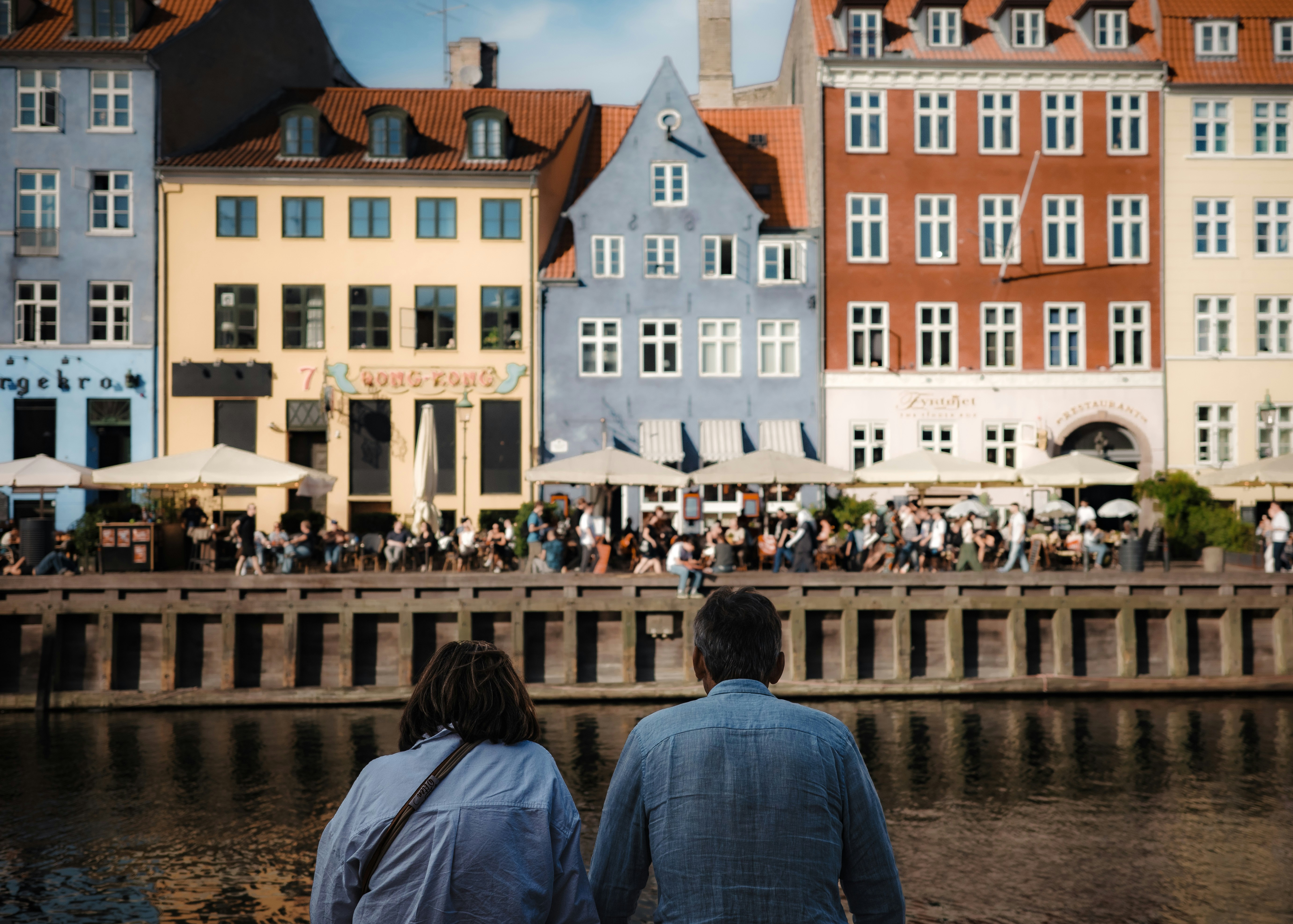 Couple Gazes Toward a Row of Pastel Houses by the Canal