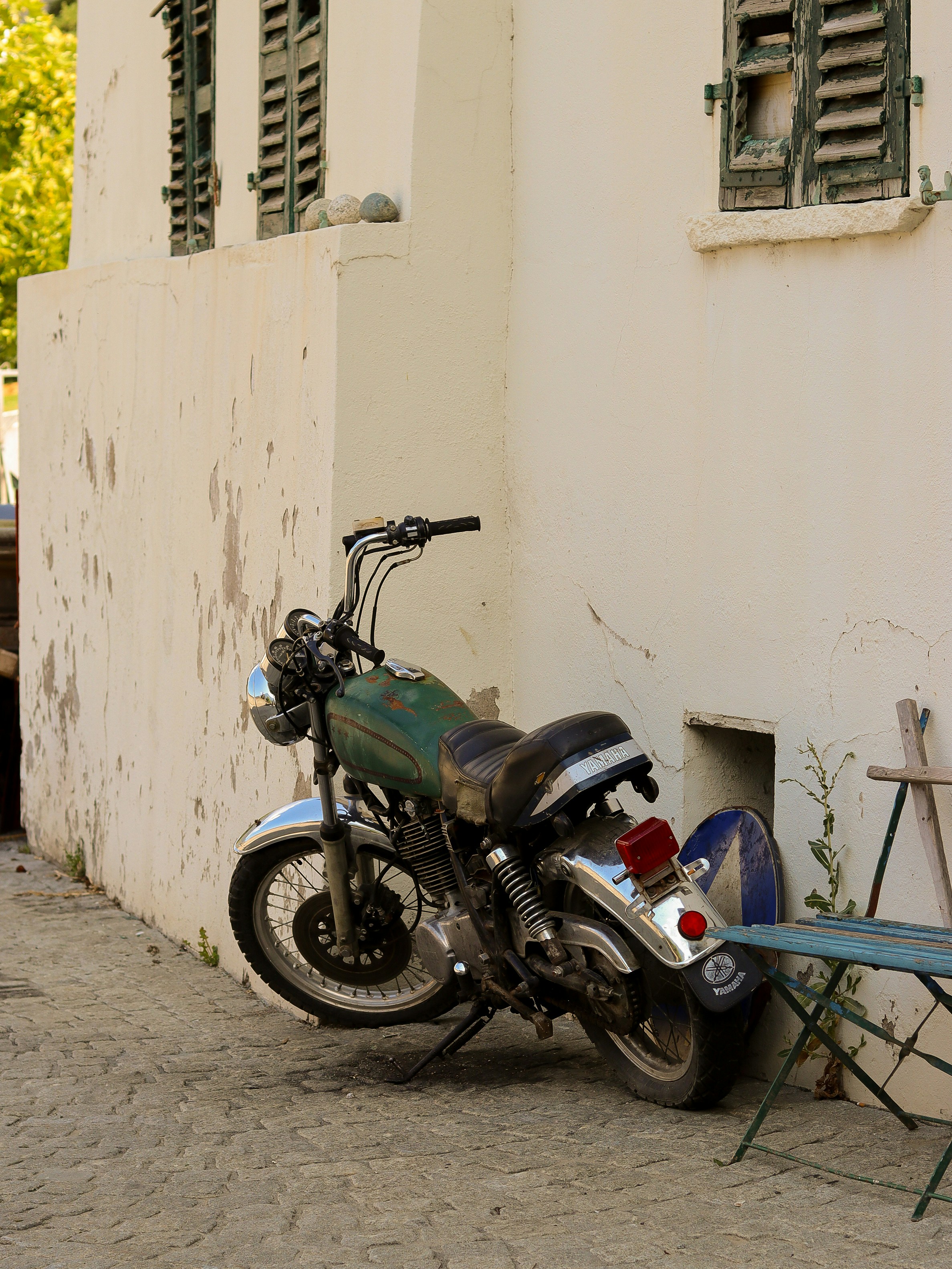 Rust and Residue: A classic motorcycle tucked against a sunlit courtyard wall