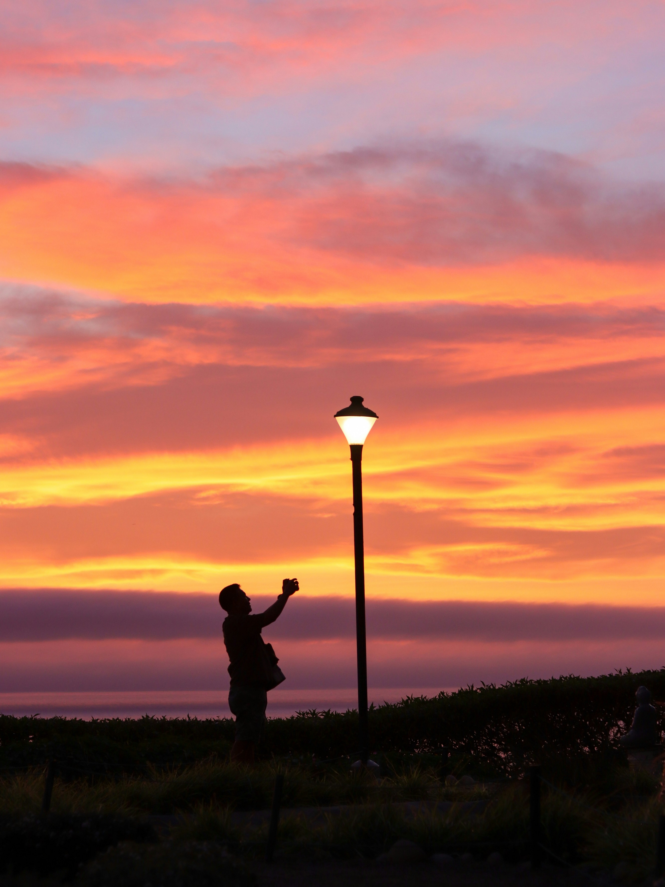 Silhouette at Dusk: A Lone Walker Reaches for the Lantern Flame