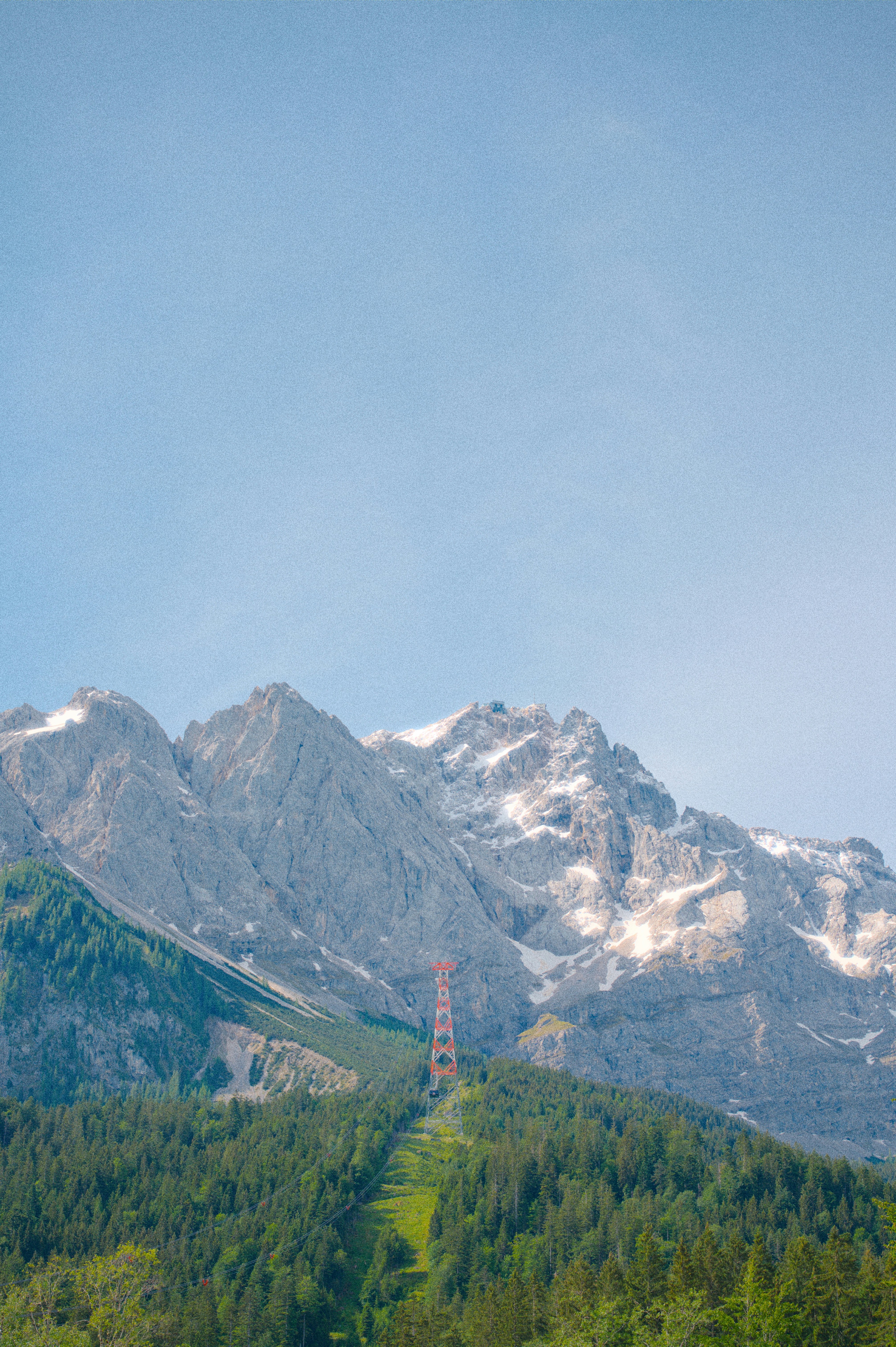 Snowy Peaks Behind a Radio Tower Crowned by Green Pines