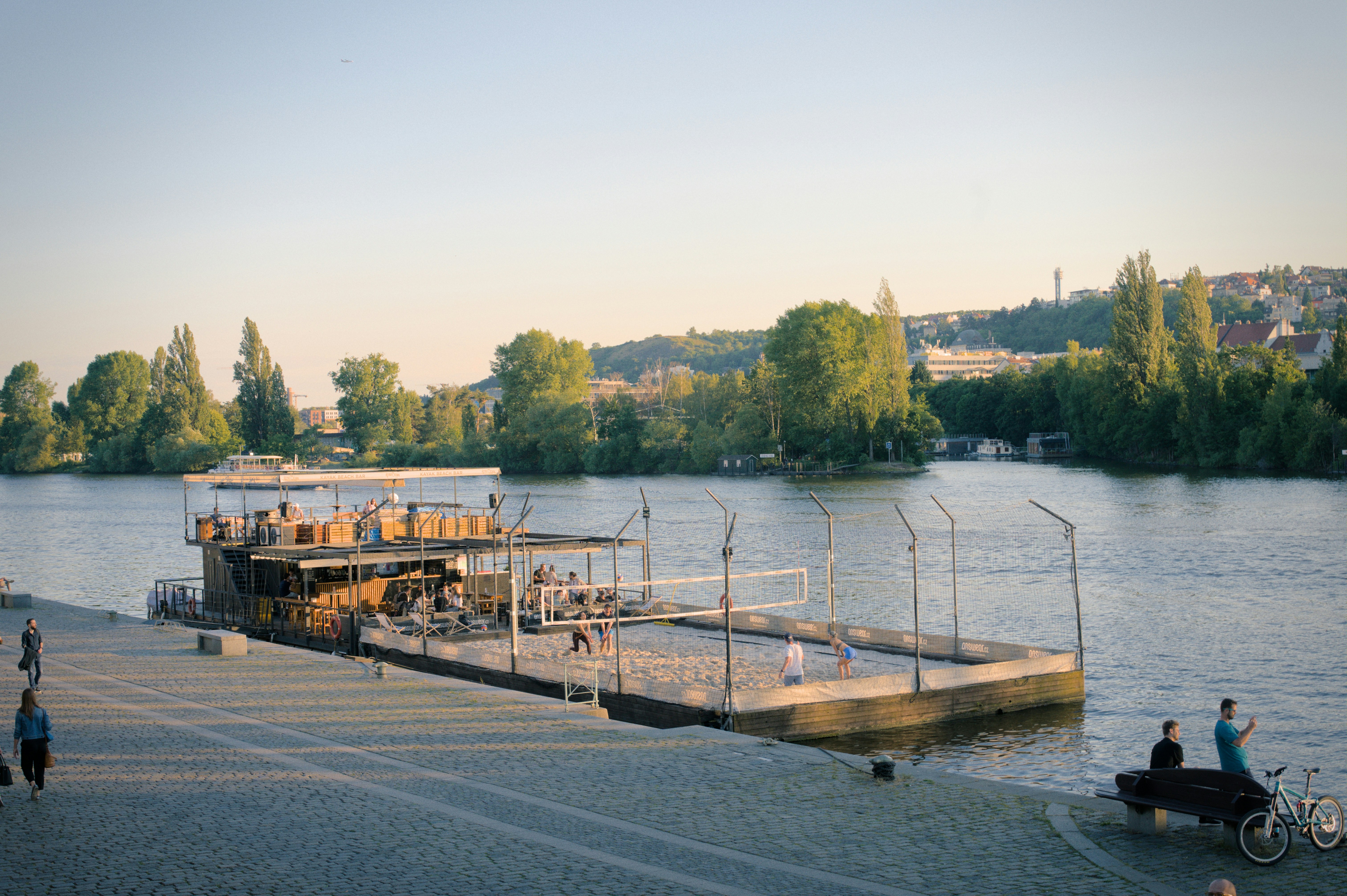Riverside Terrace at Dusk: A Busy Floating Platform Framed by Trees
