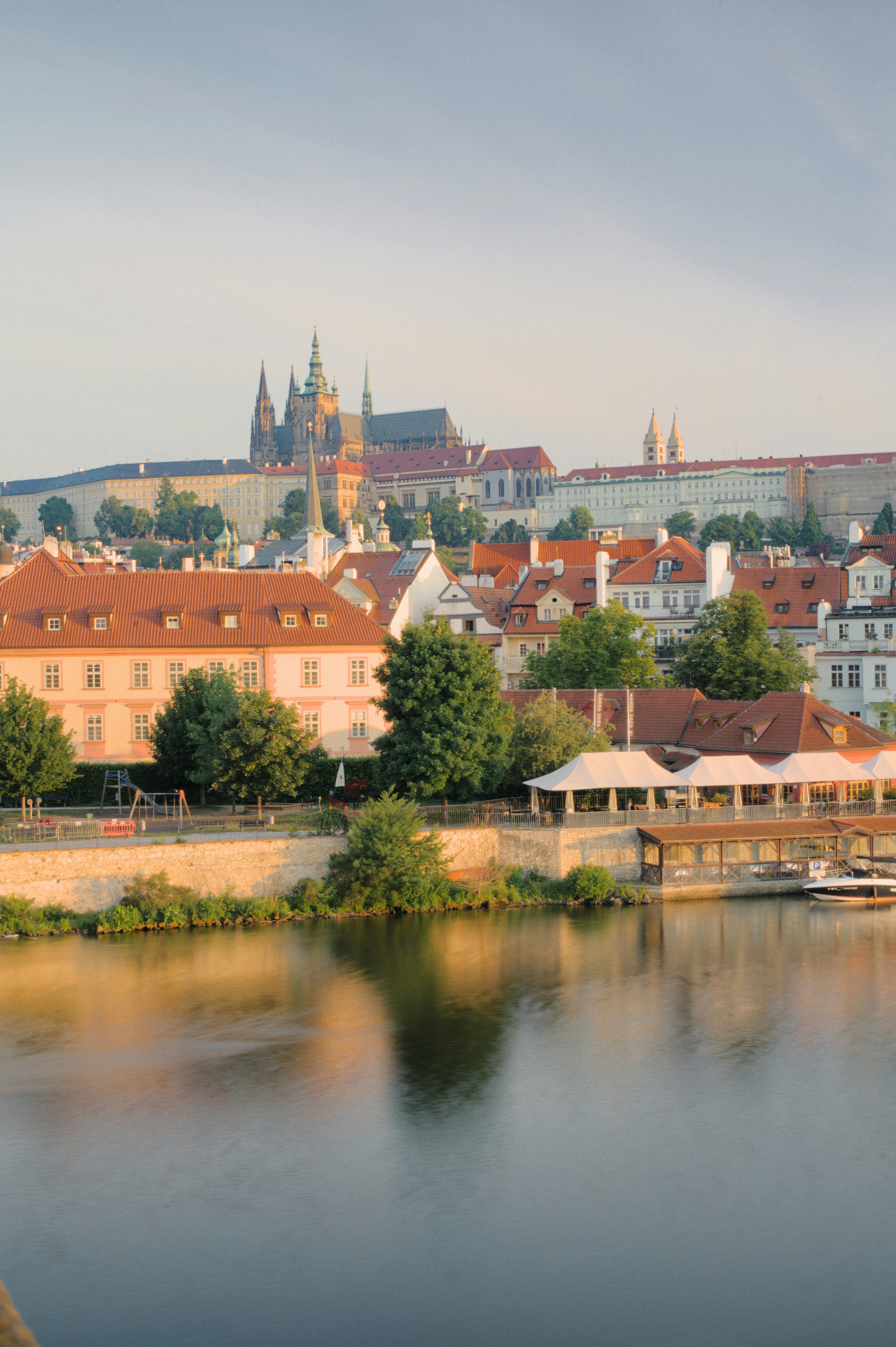 Riverside Prague-like Cityscape with Red-Tiled Roofs and Historic Spires