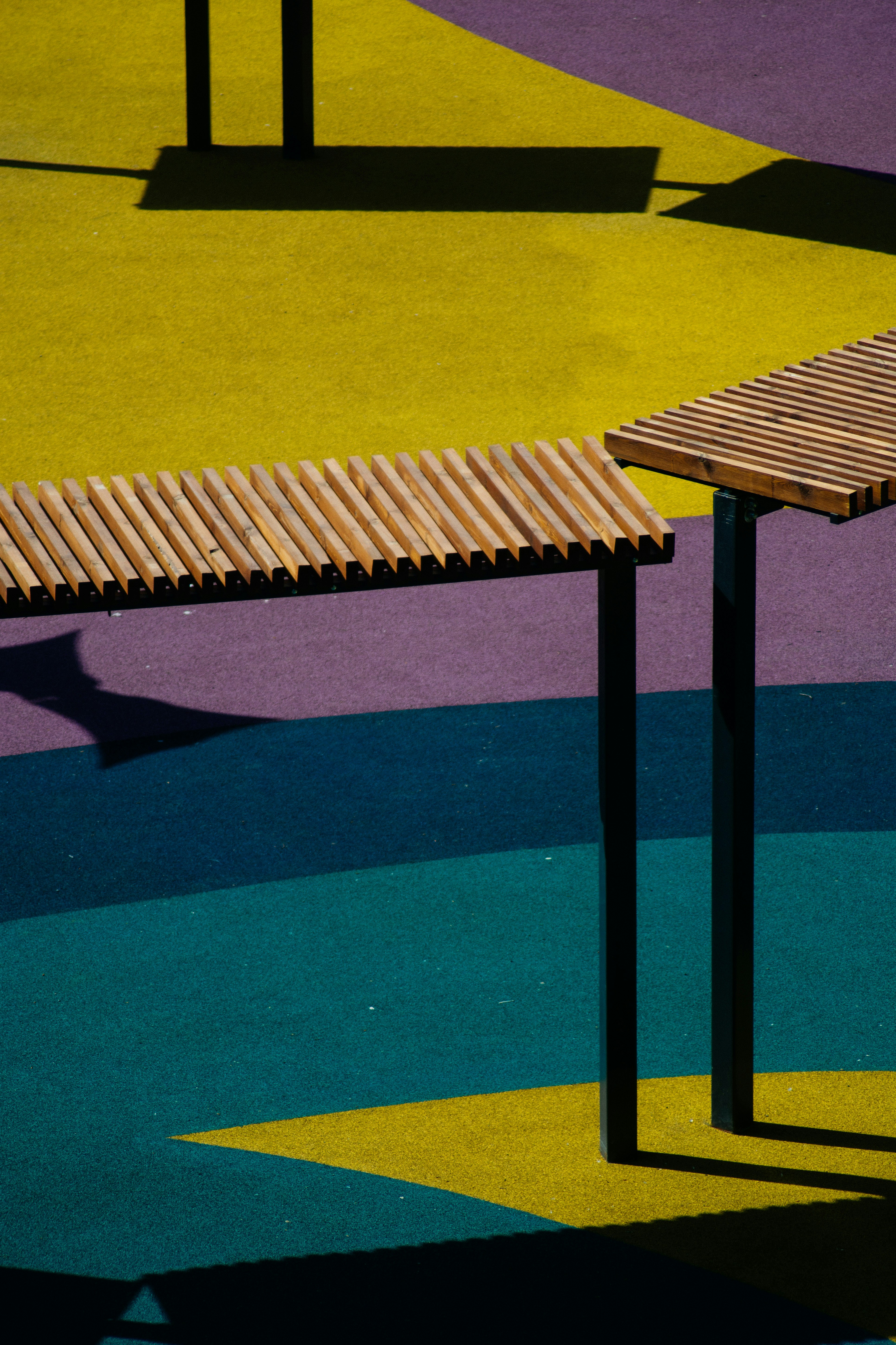 Shadowed parallelograms: wooden slats over a colorful playground canvas