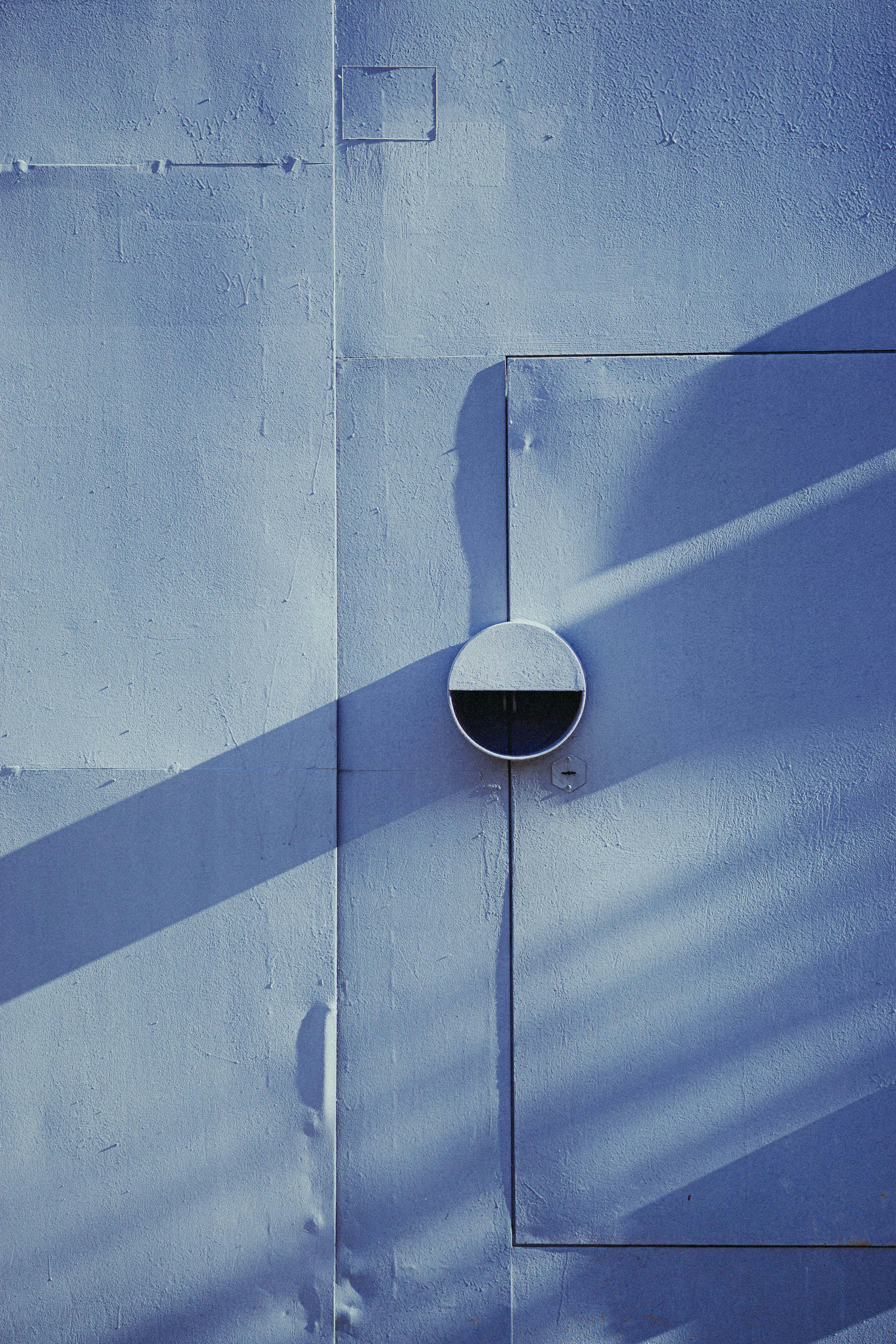 Cool Blue Facade with Shadowed Pipe Cut Across Geometric Planes