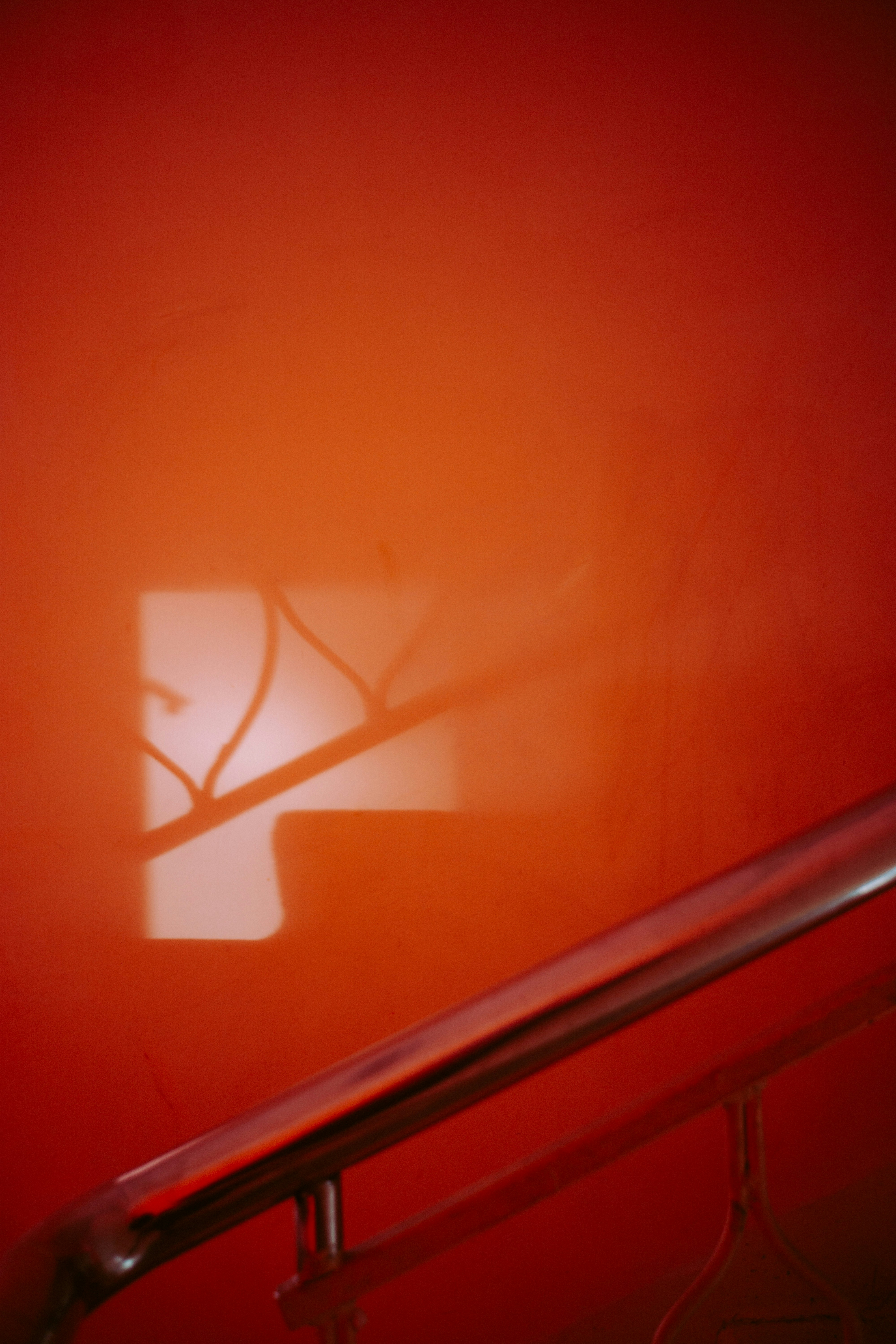 Red Corridor: A Quiet Glint of Window Light in the Handrail Frame