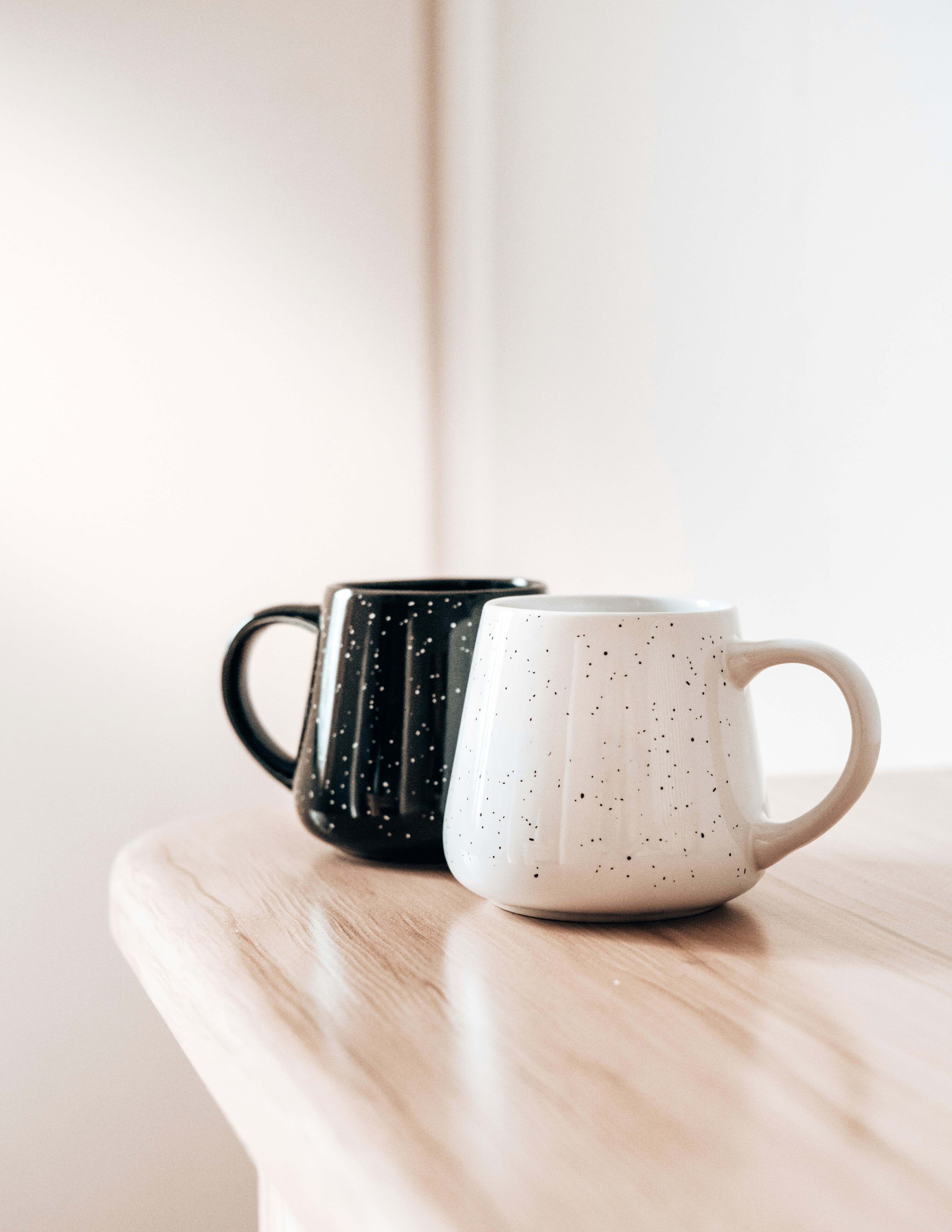 Handshake of Ceramics: Two Speckled Mugs Rest on a Sunlit Table