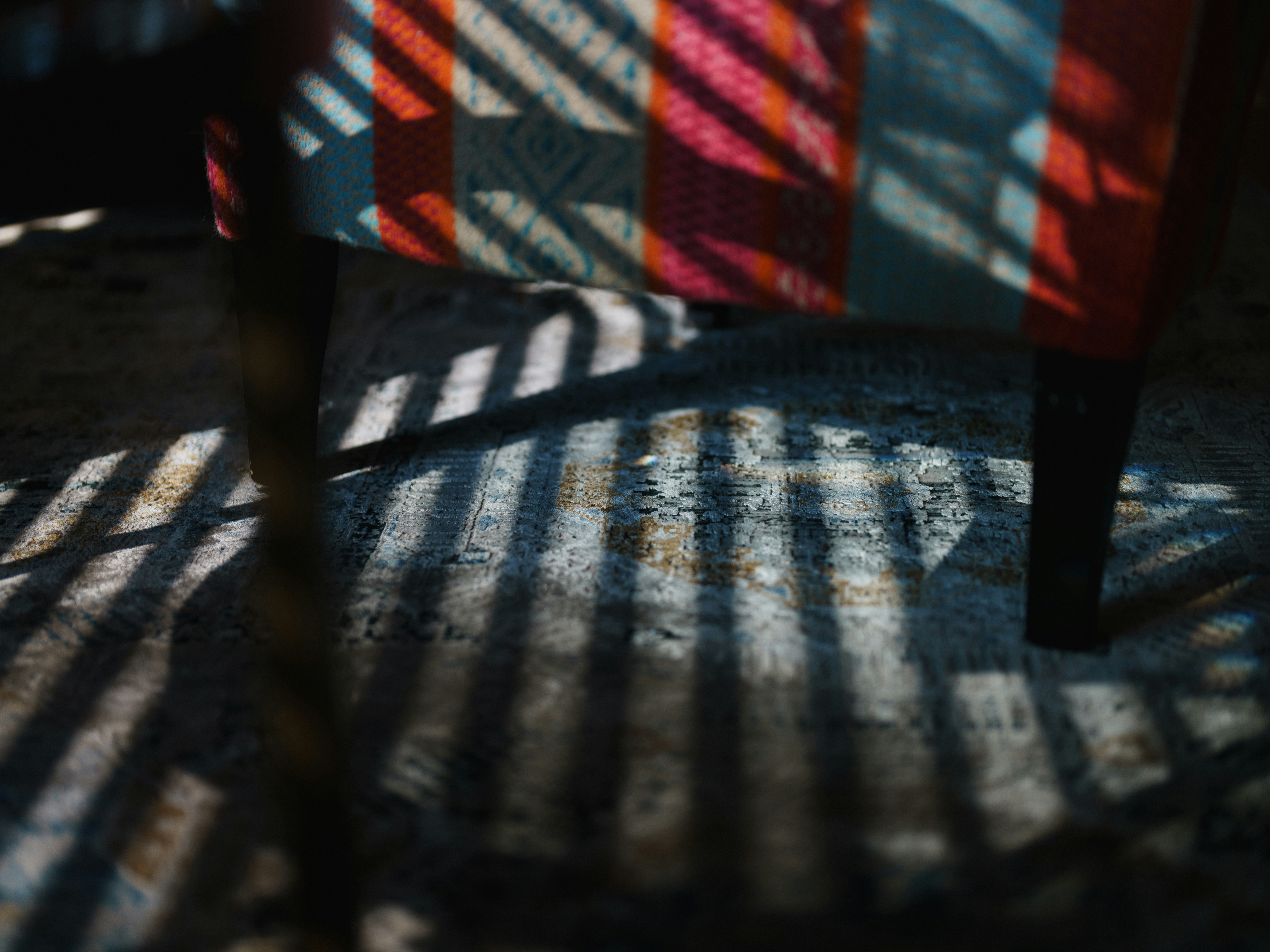 Shadowed Stripes: Sunlit Thread of a Rug Beneath a Table