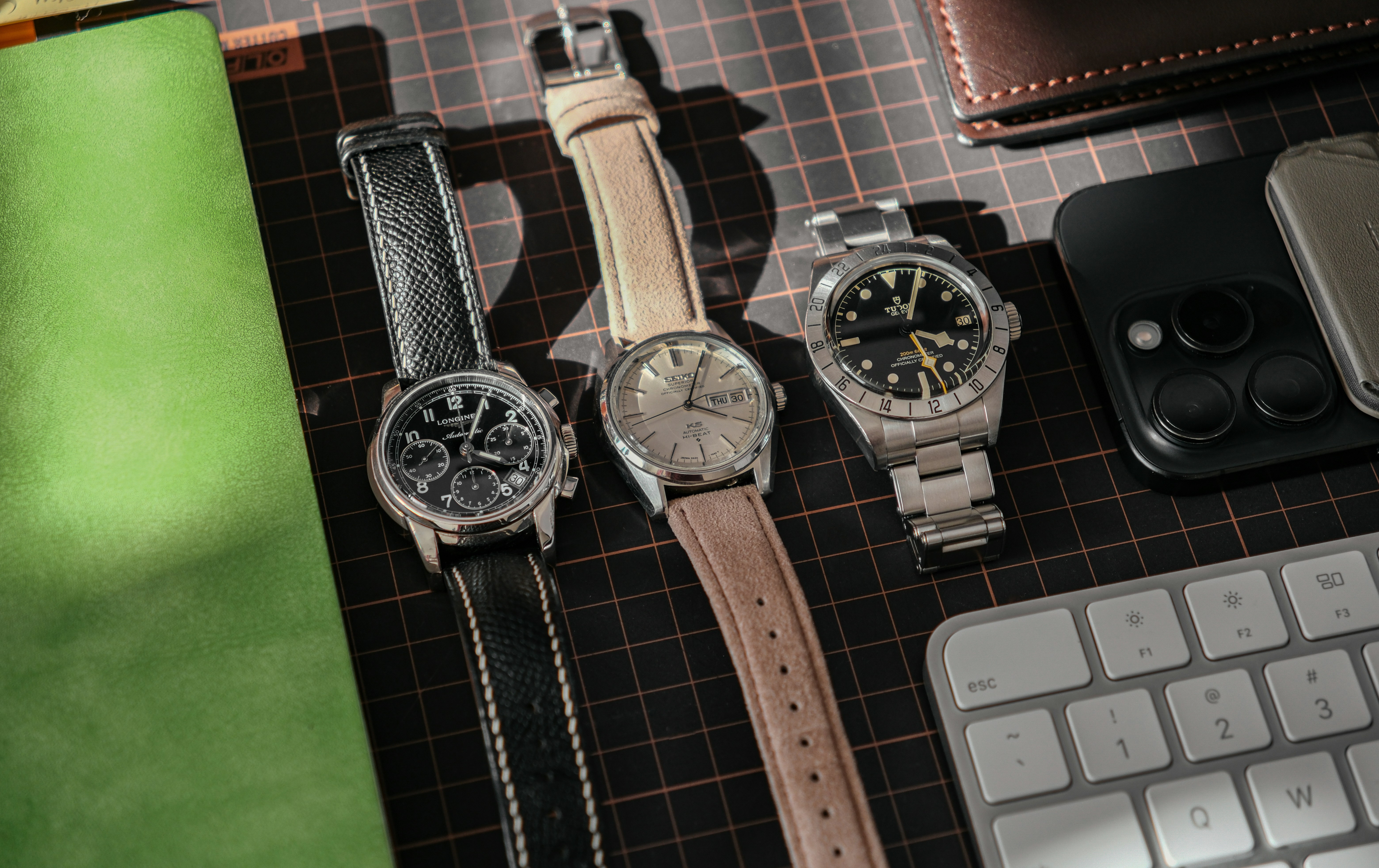 Timekeepers on a Grid: Four Wristwatches Framed by a Tech Workspace
