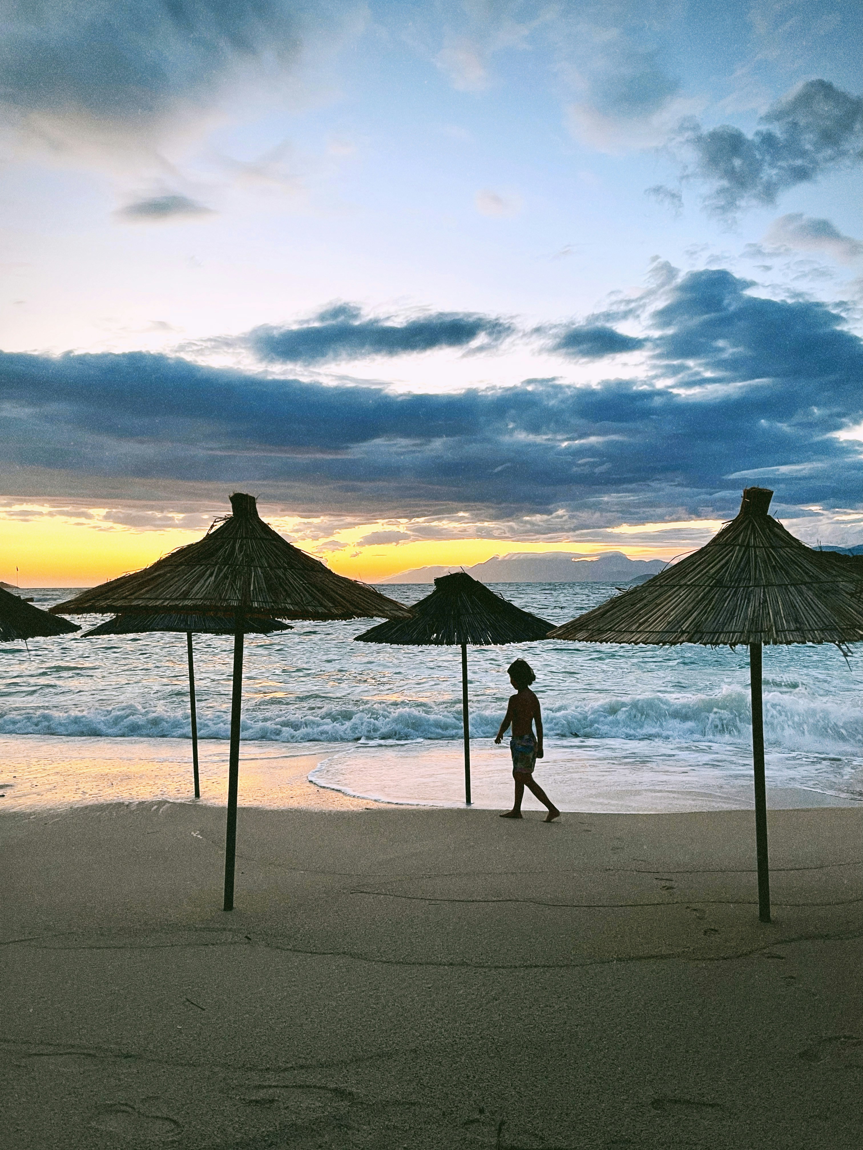 Sunset Stride by the Sea with Thatched Umbrellas