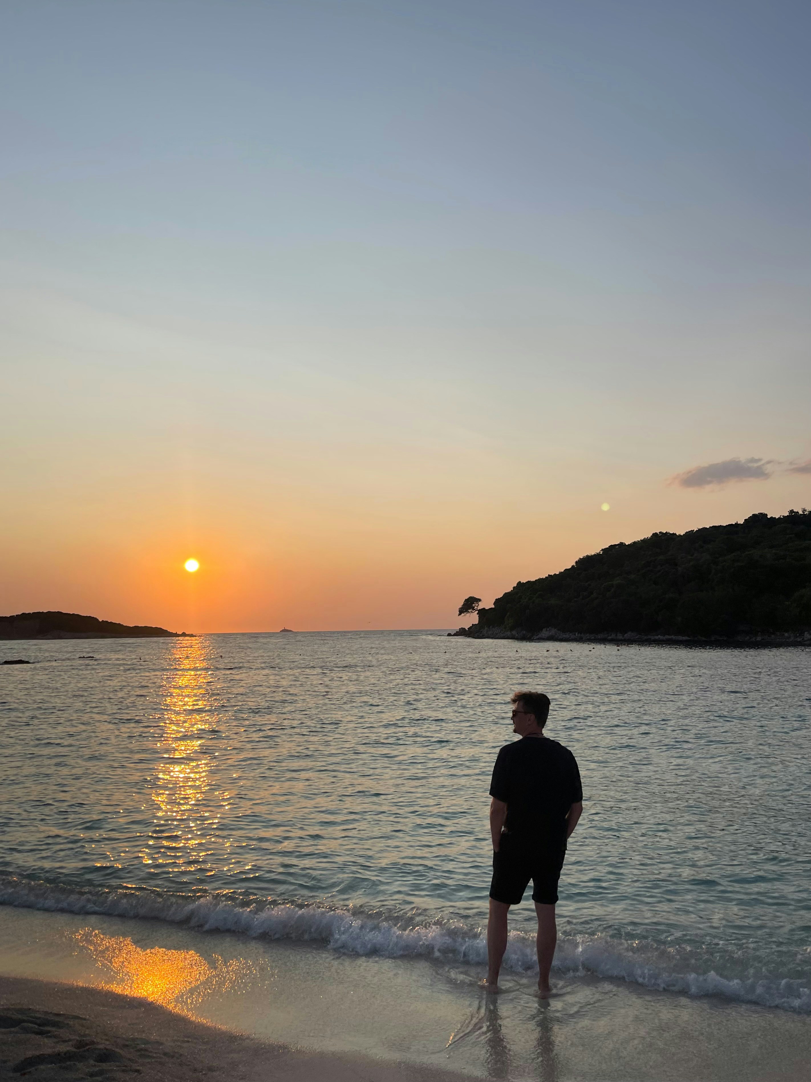 Sunset Silhouette: Man Stands at the Edge of Quiet Waters