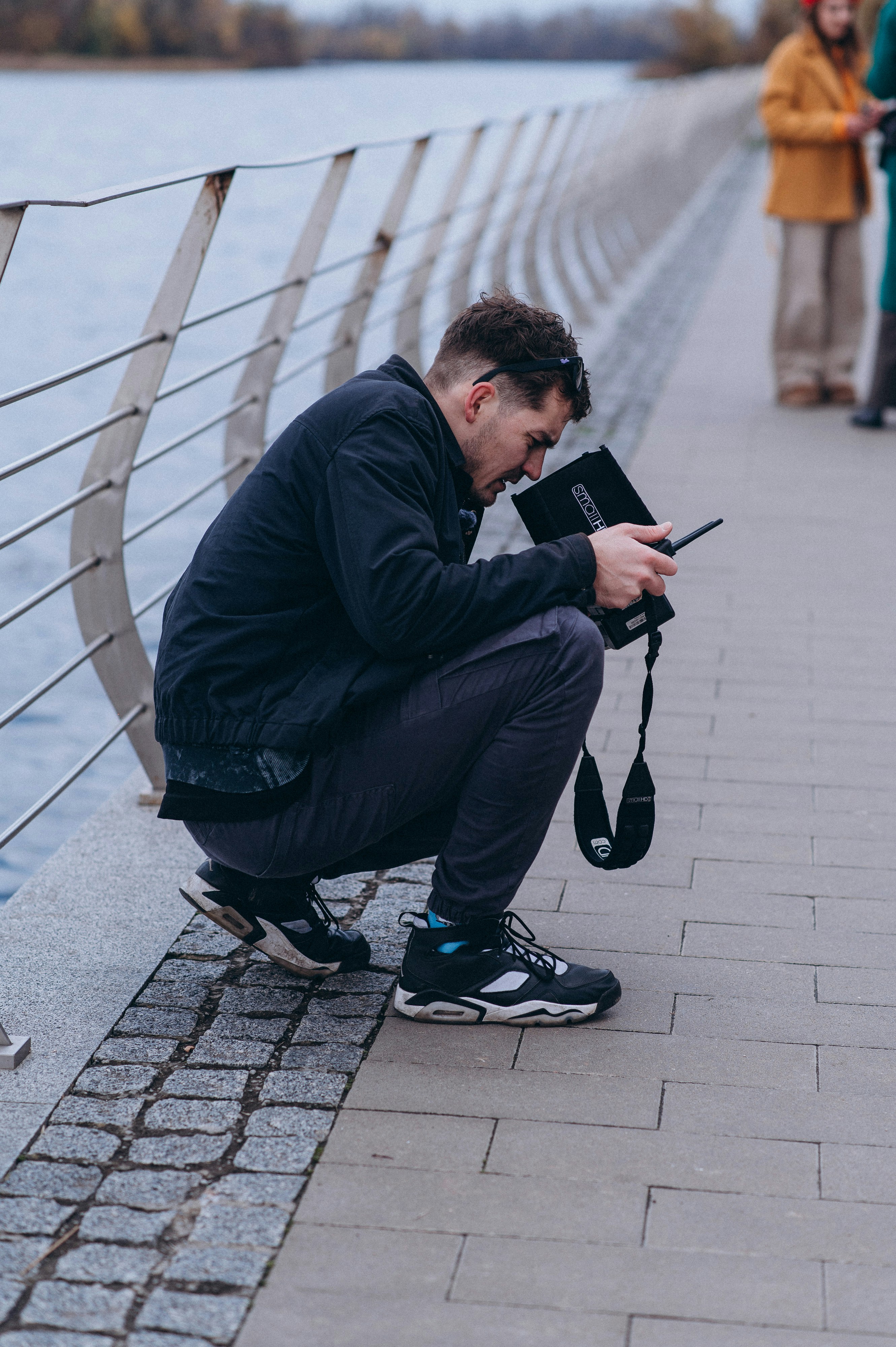 Kneeling on the Quay: Photographer's Focus Amid Waterfront Calm