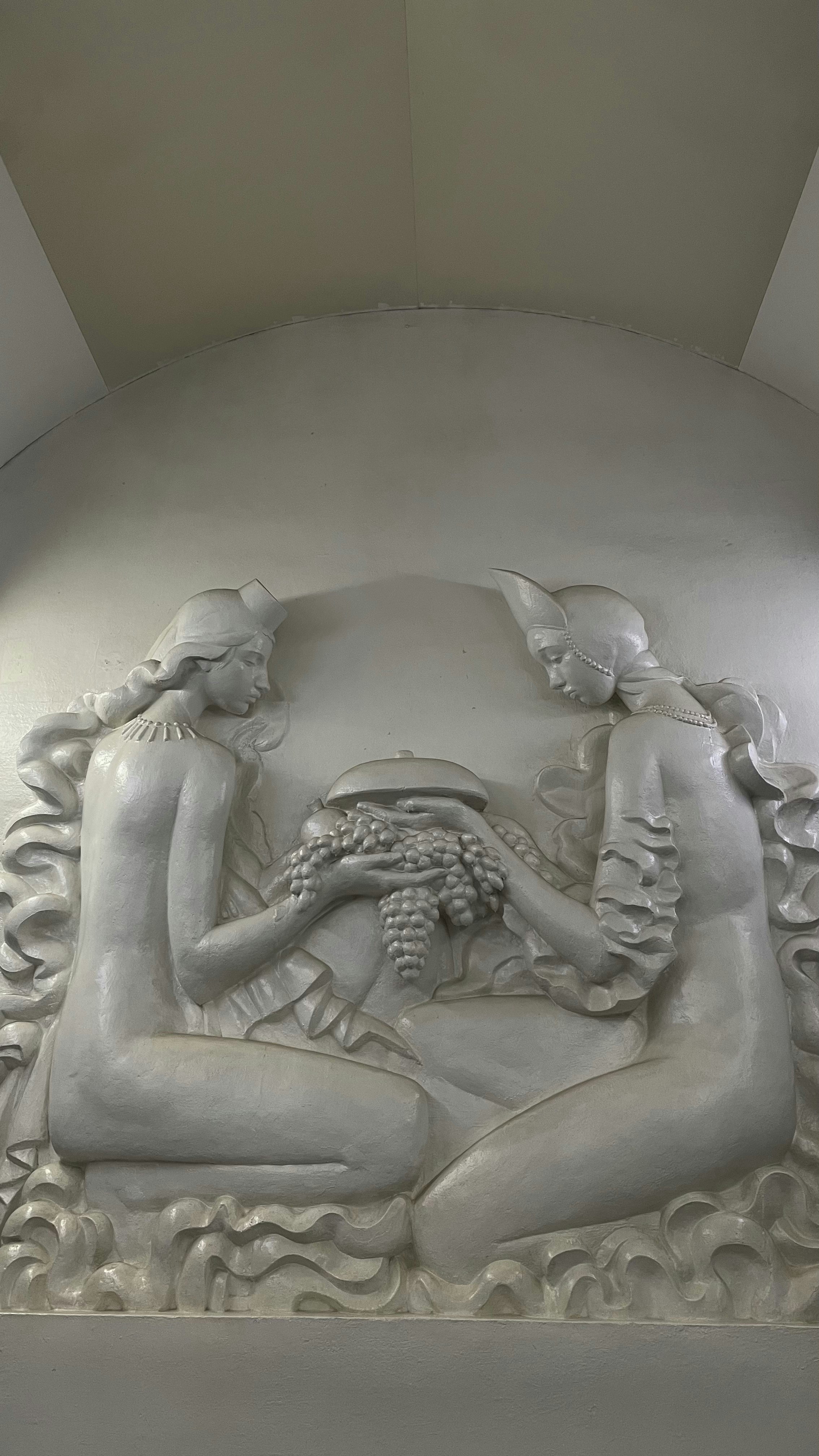 Carved Quiet: Two Figures Weighing a Grapevine Offering
