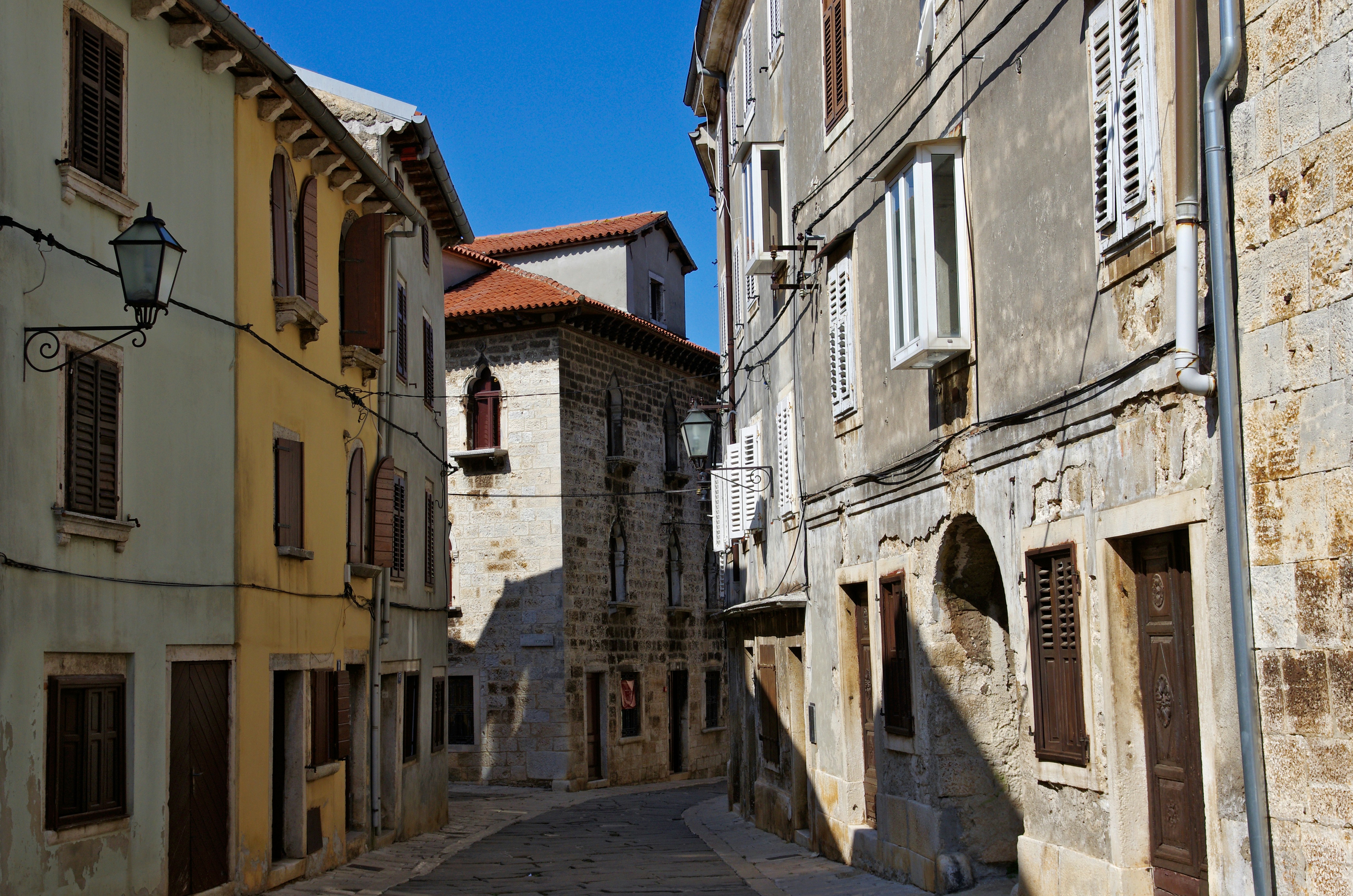 Sunlit Alleyway Between Weathered Facades