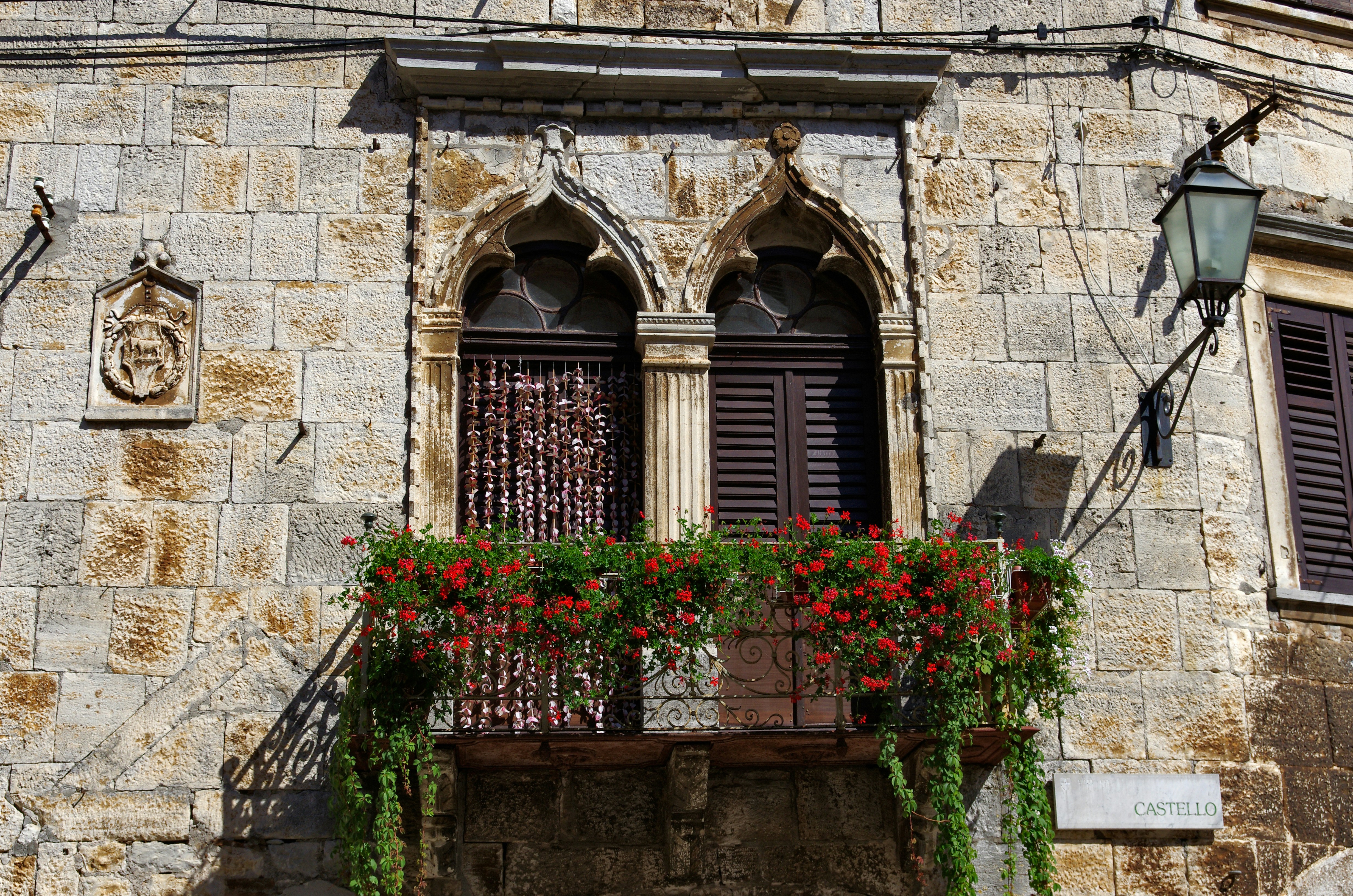 Balcony of Crimson Blossoms Over Weathered Stone
