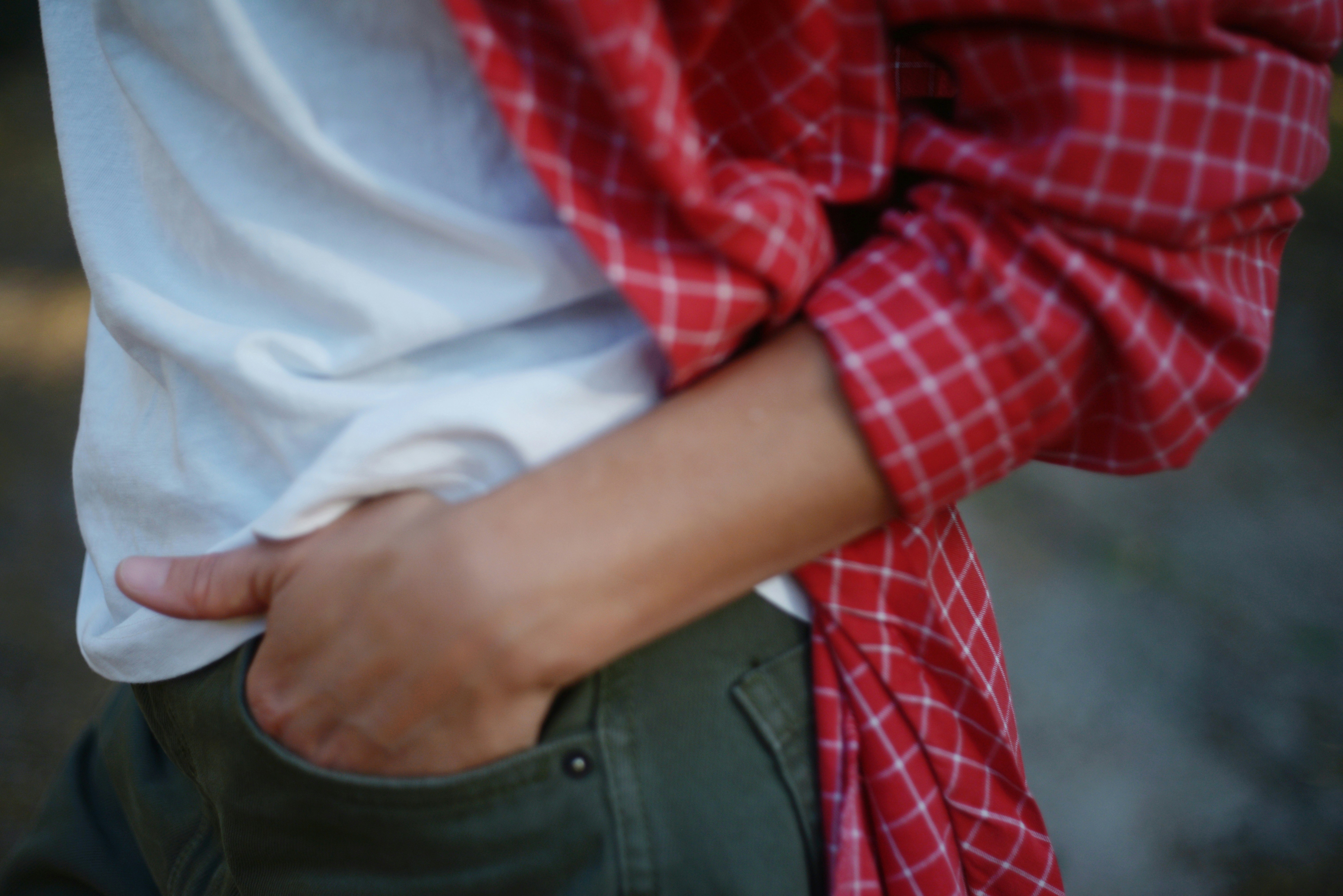 Hands in the Frame: A Casual Moment with Red Plaid Draped Over Green Jeans