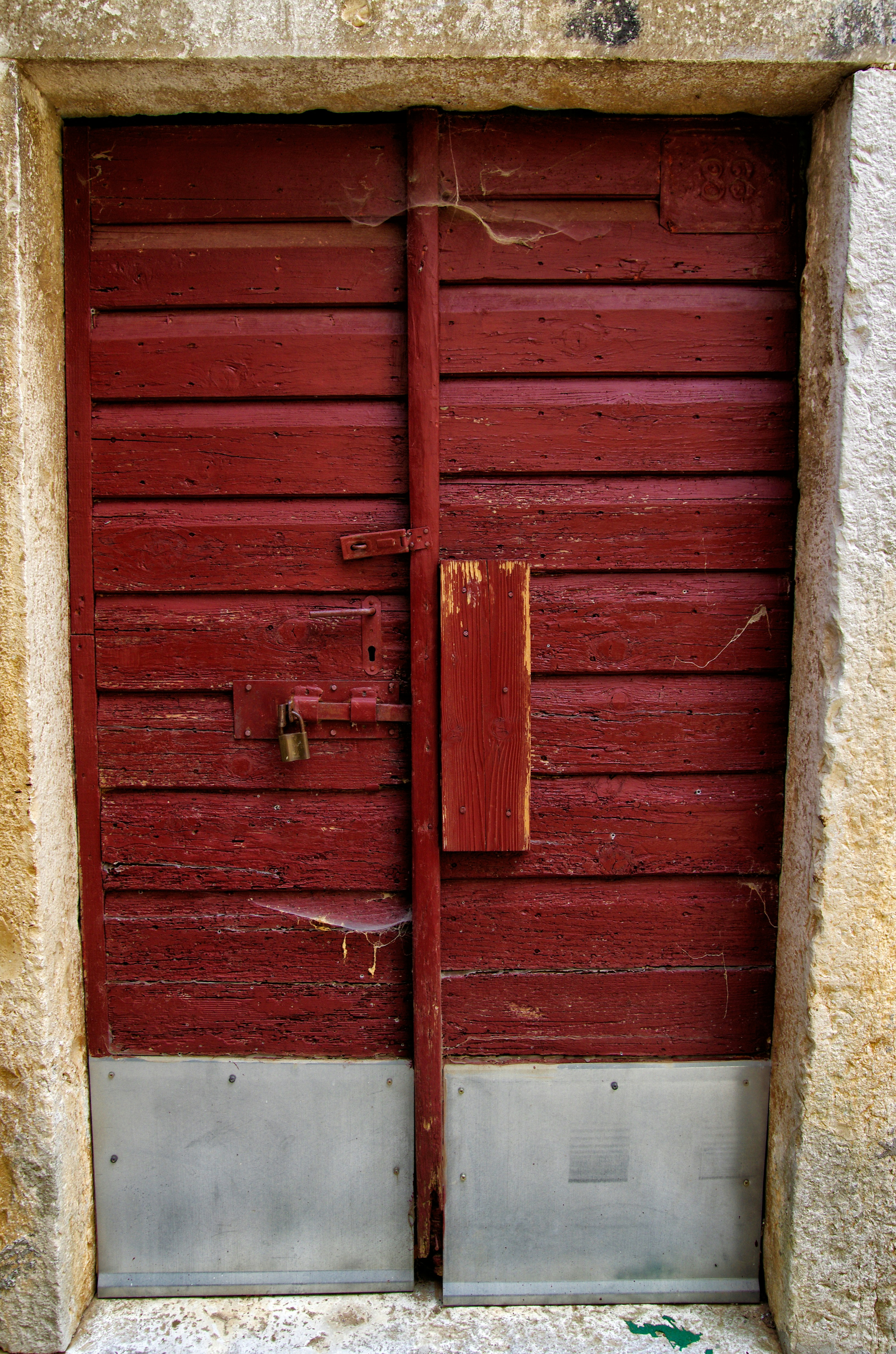 Weathered Red Door: A Rustic Frame Framed by Stone and Steel