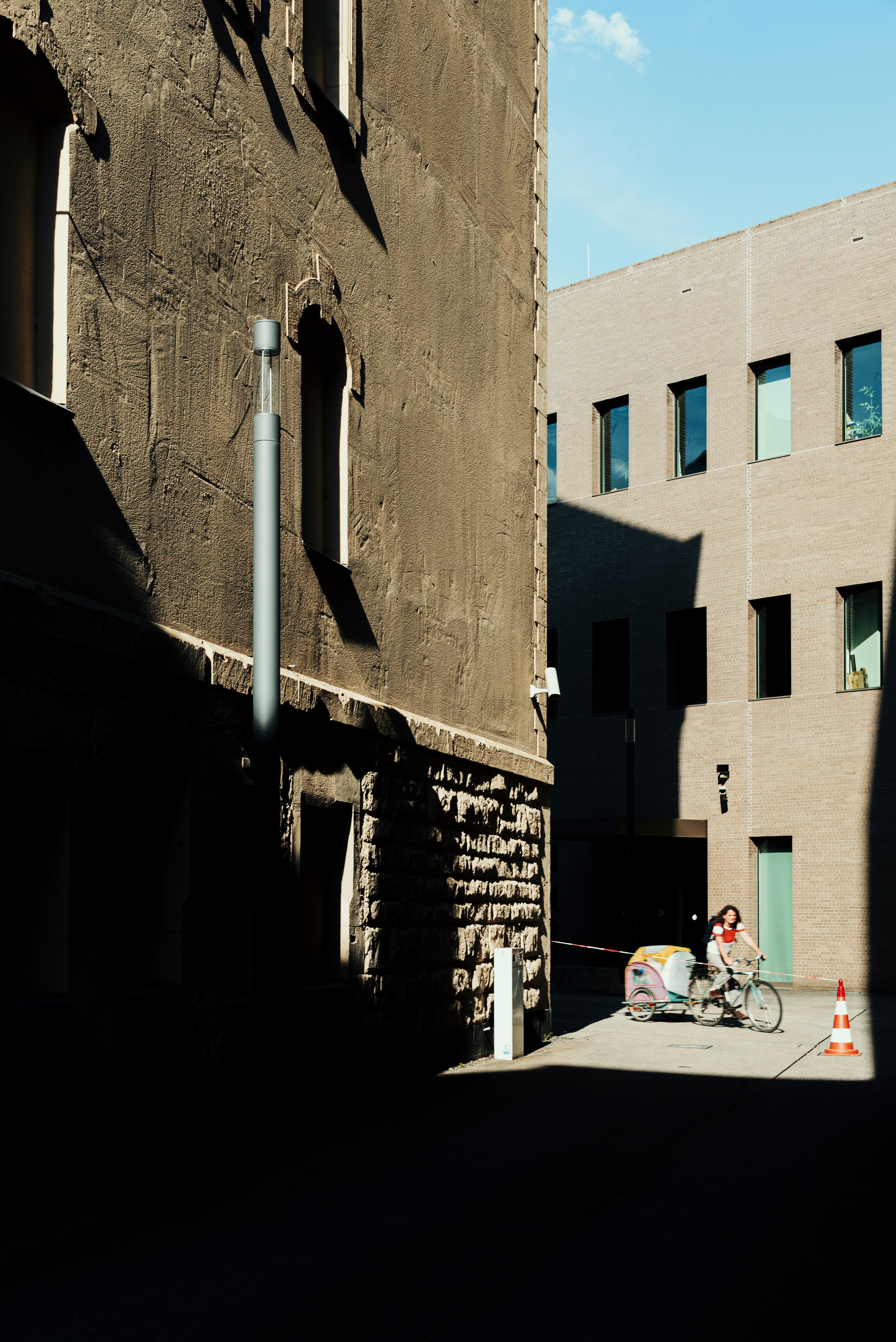 Sunlit Alley: A Cyclist Pausing in the Shadowed Gap