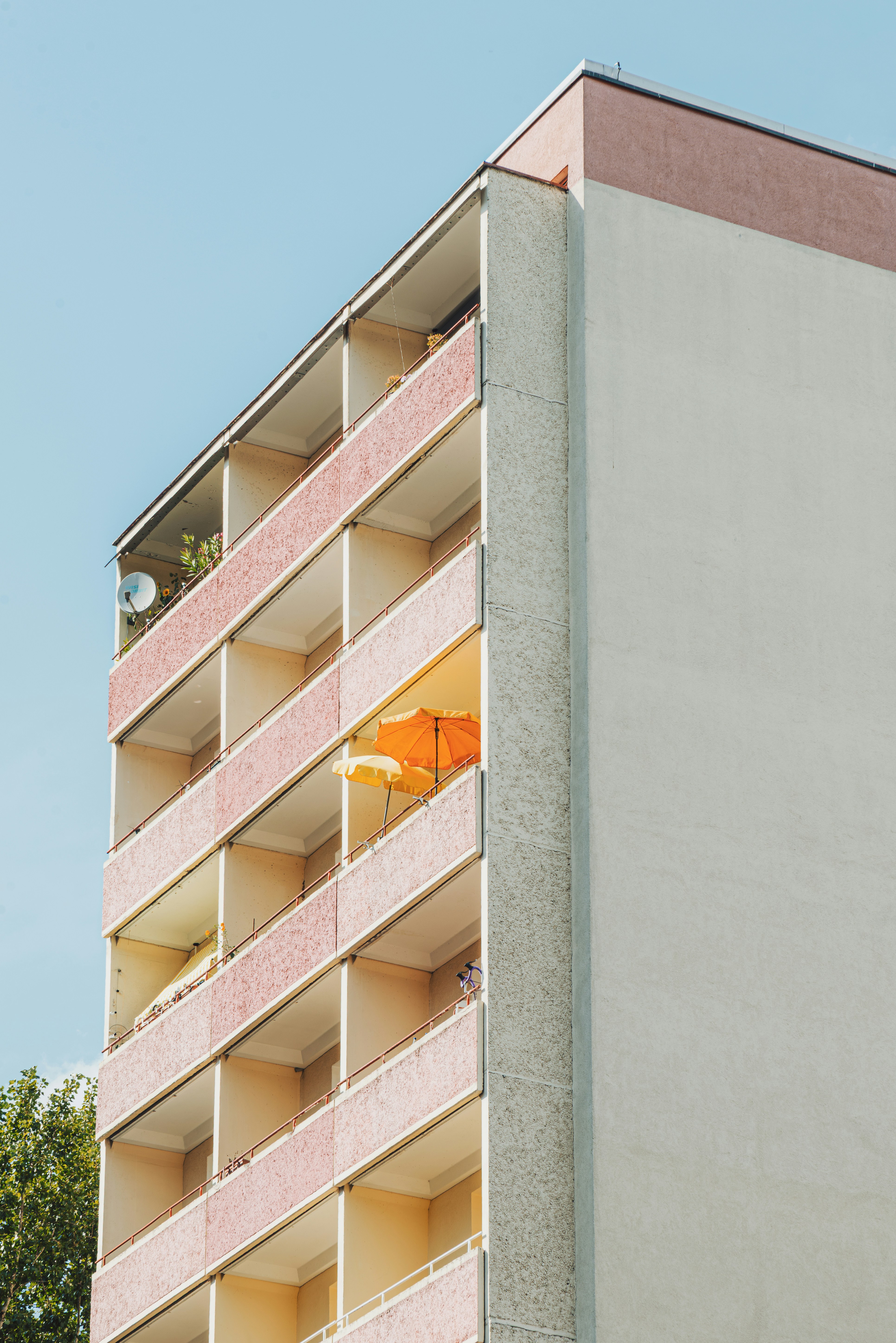Sunlit Balcony Row: Coral Shutters Against a Clear Sky