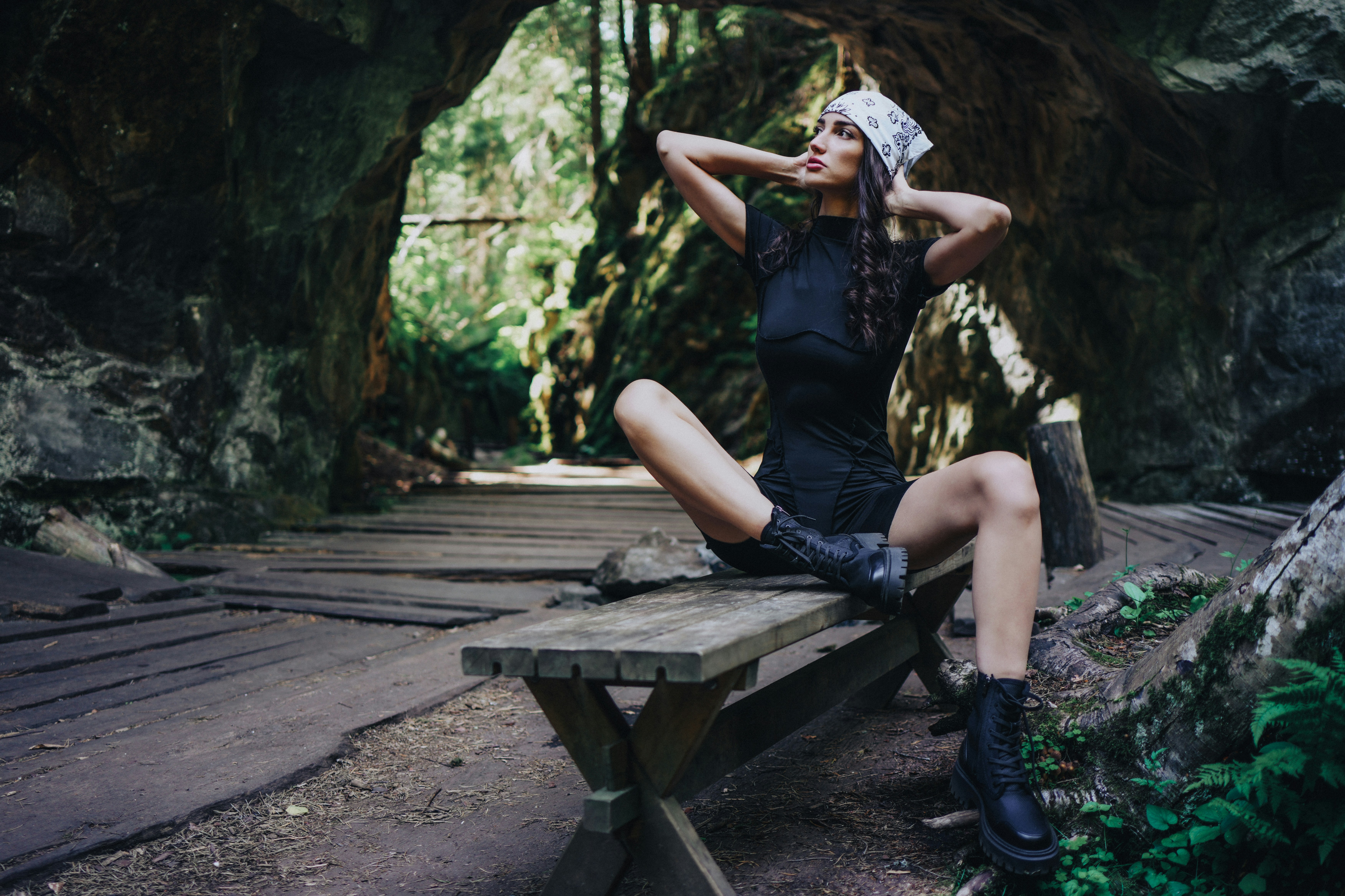 Woman in Black Outfit Poses Within a Rock Corridor